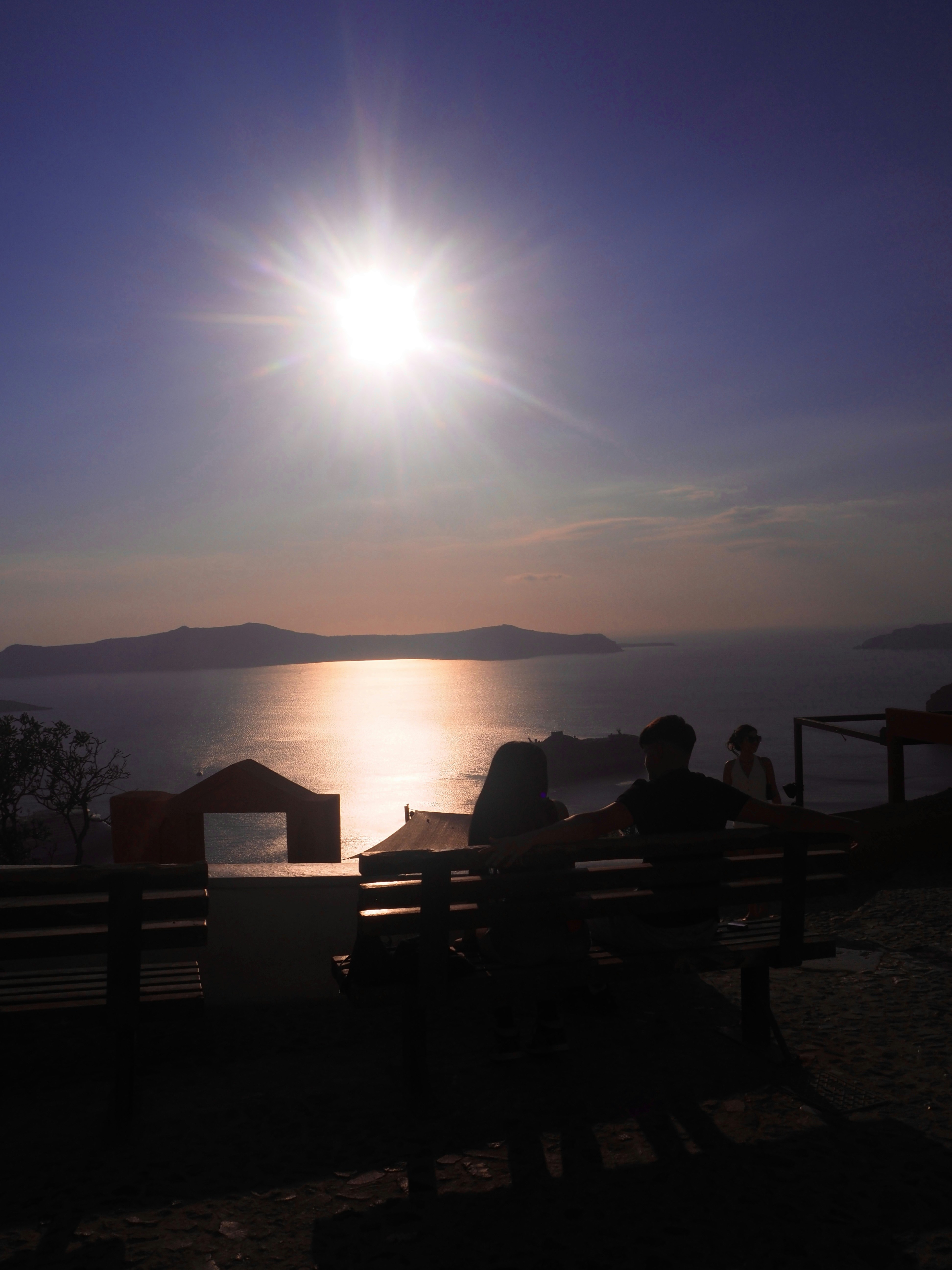 Sunlit overlooking terrace: silhouettes against a sea-horizon glow