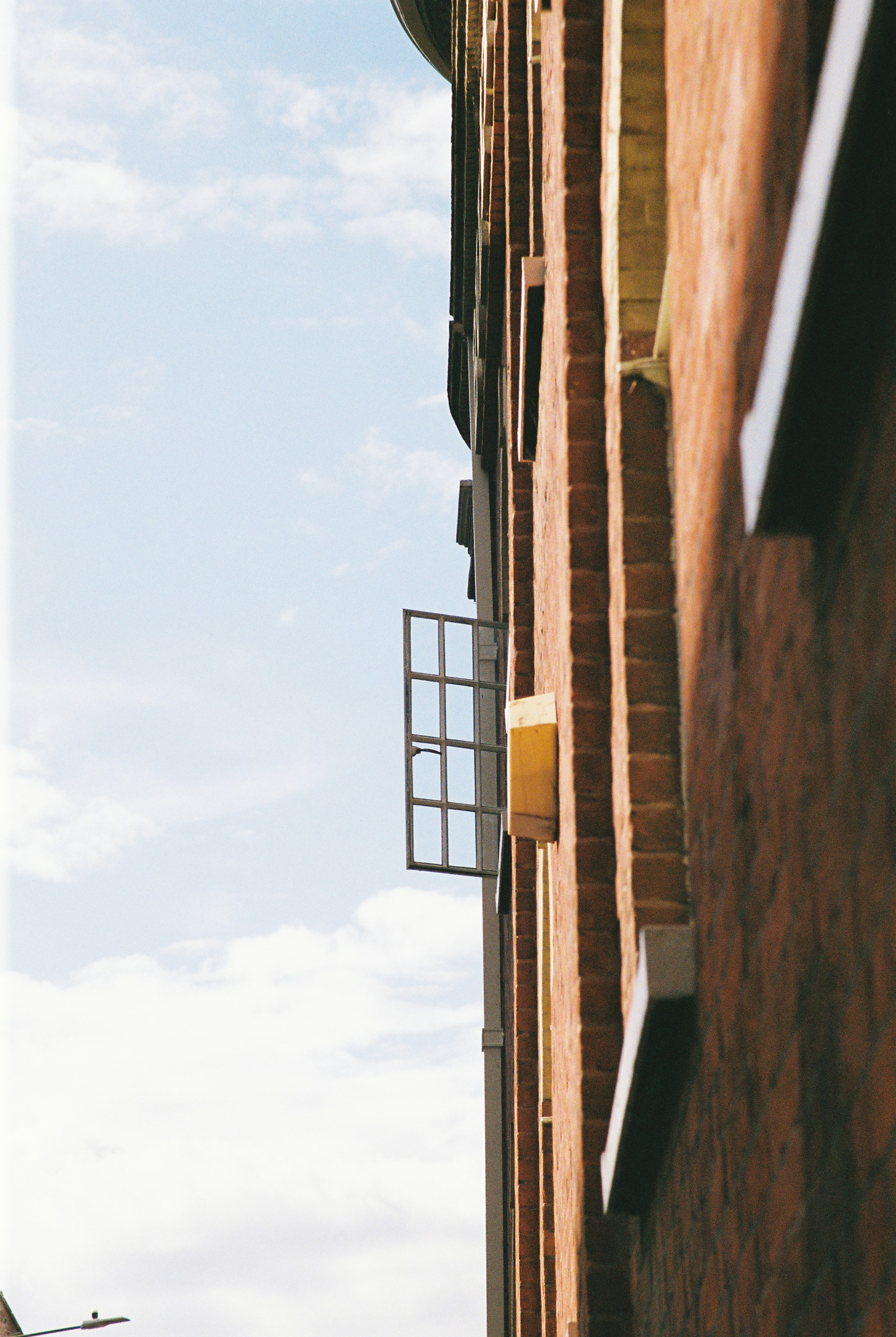 Brick Facade in Perspective: A Vertical Shot of a Street-Height Wall with Metal Balcony Frame
