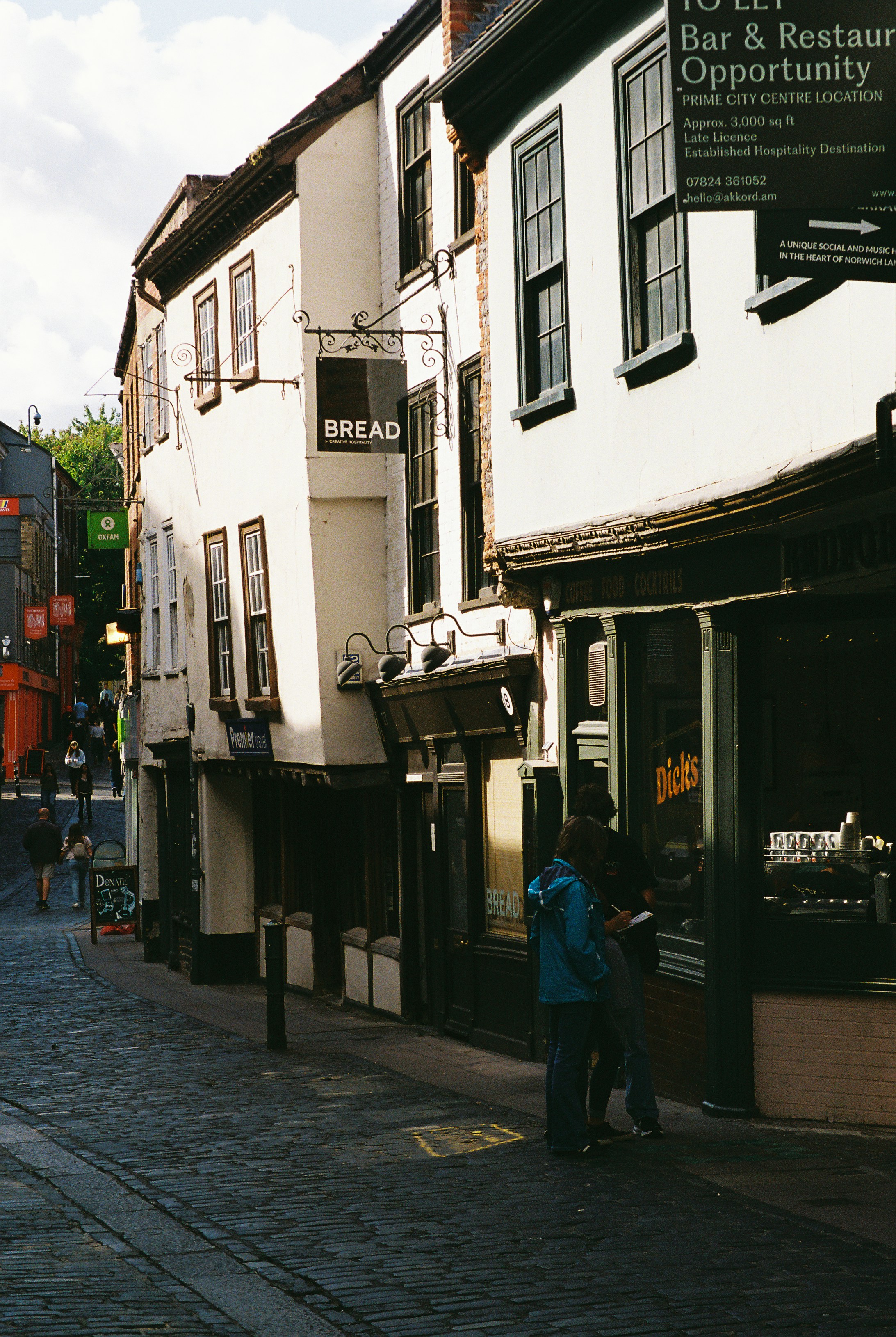 A Quiet Cobbled Street Jostle: Bread Sign and Shopfronts in Dappled Sun