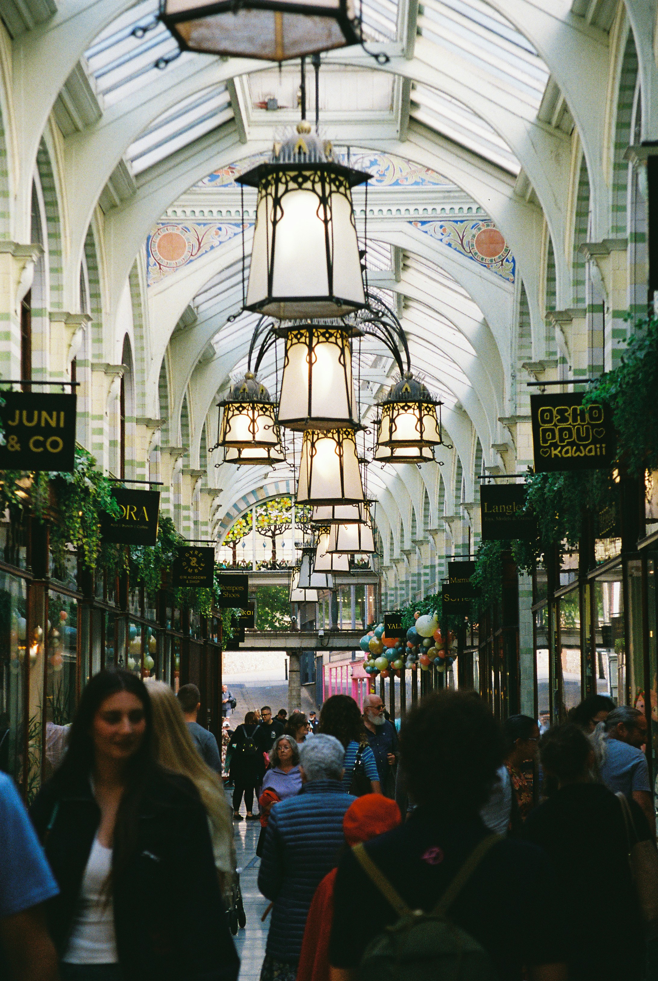 Lantern-lit Arcade: A Corridor of Shoppers under Skyward Glass