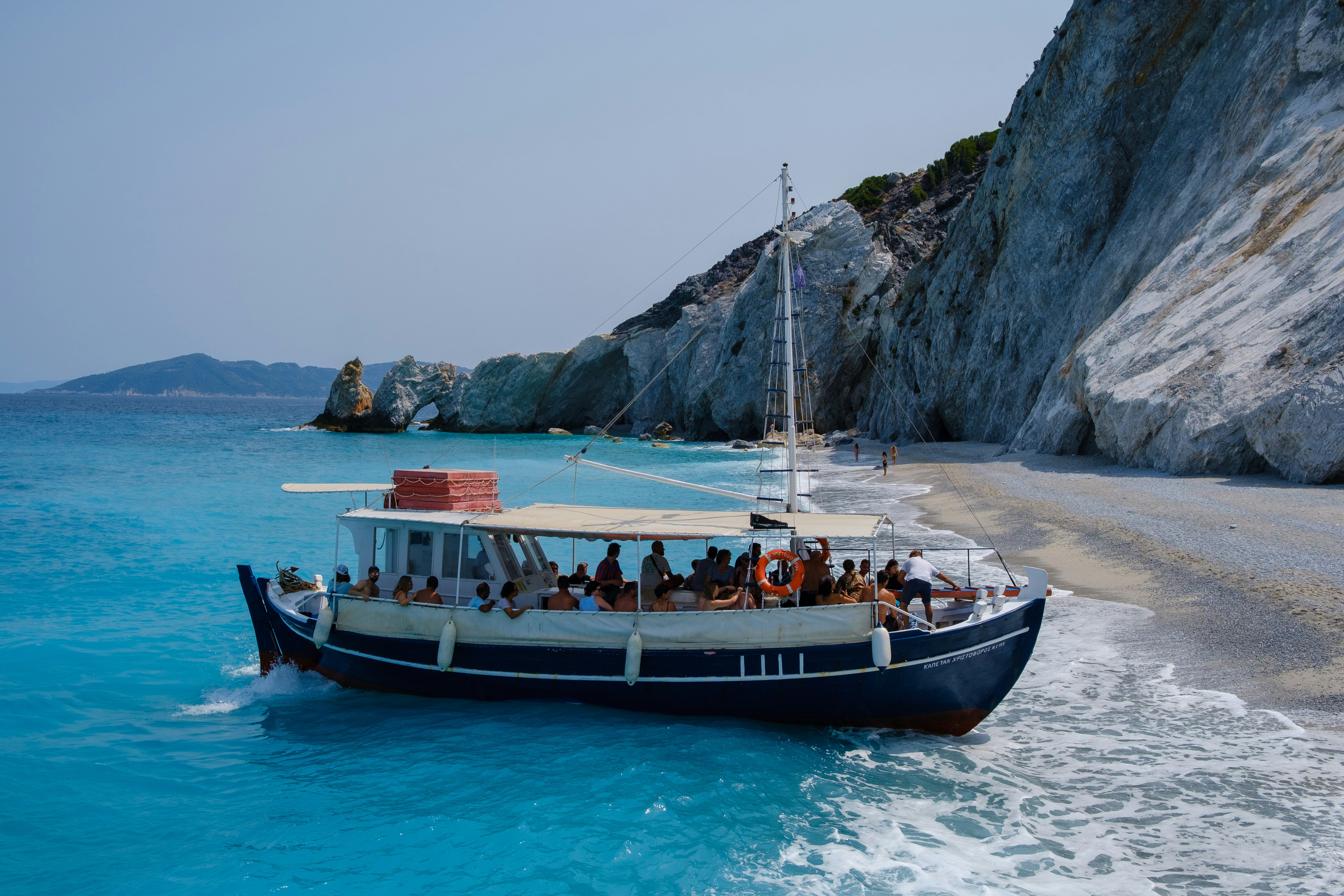 Azure Vessel Anchored at a Cliffside Bay