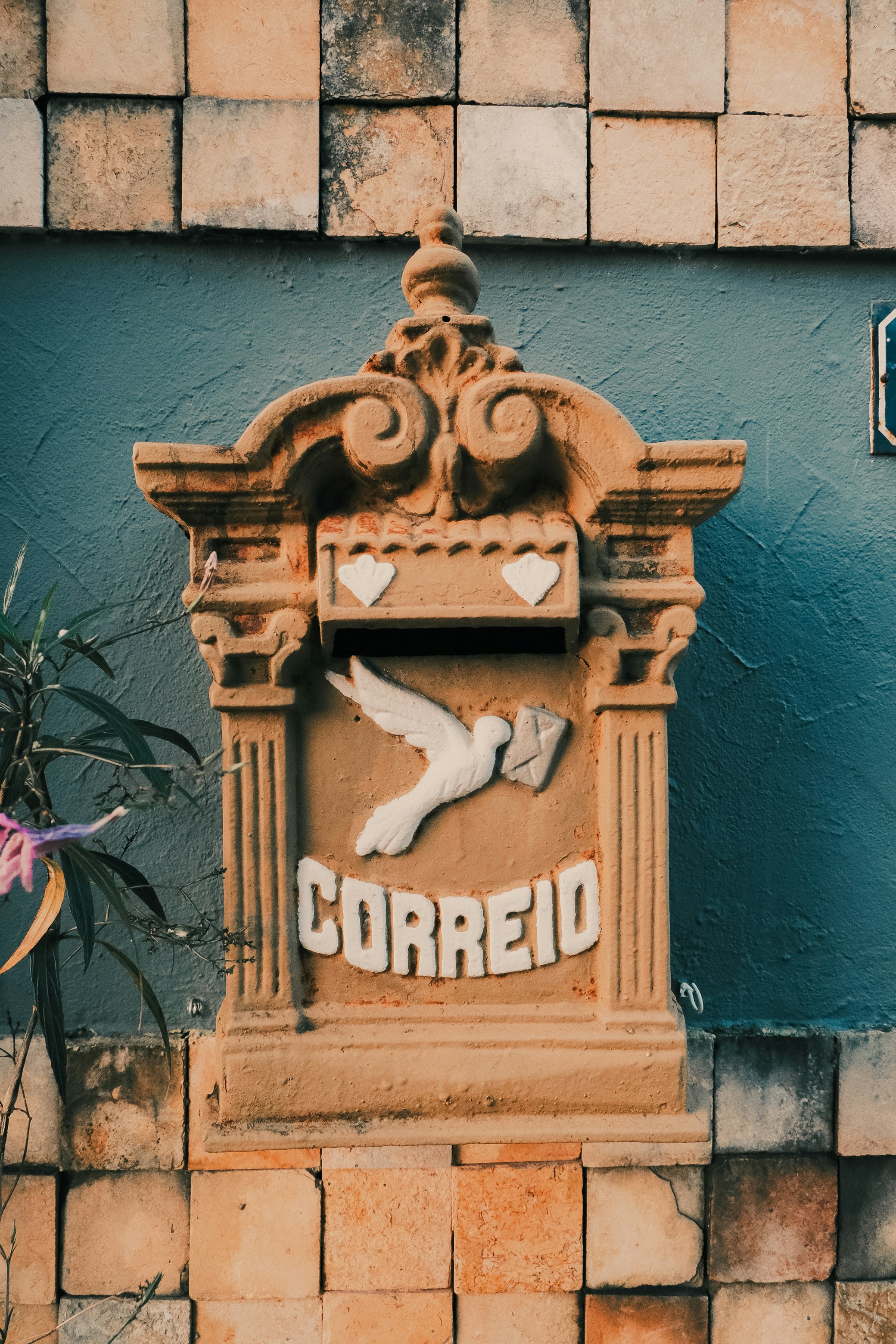 Stone Co‑Creator: A Decorated Mailbox Statue Anchored by Blue Brickwork