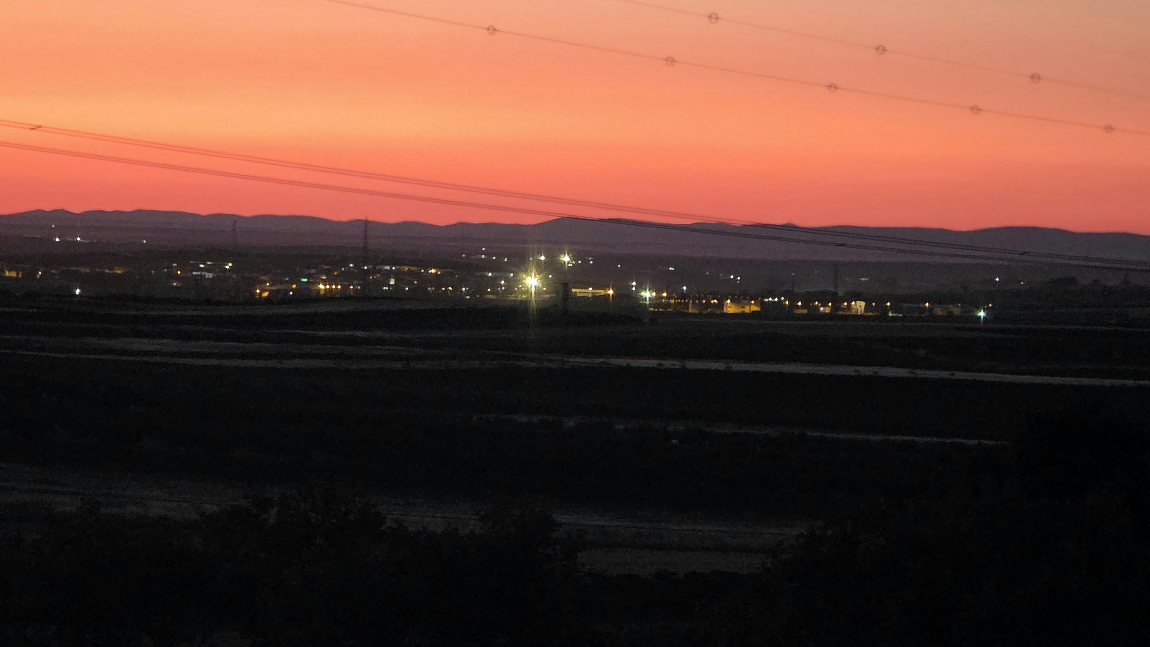 Dusk Over Flatlands: City Lights Spark Against a Slumbering Horizon