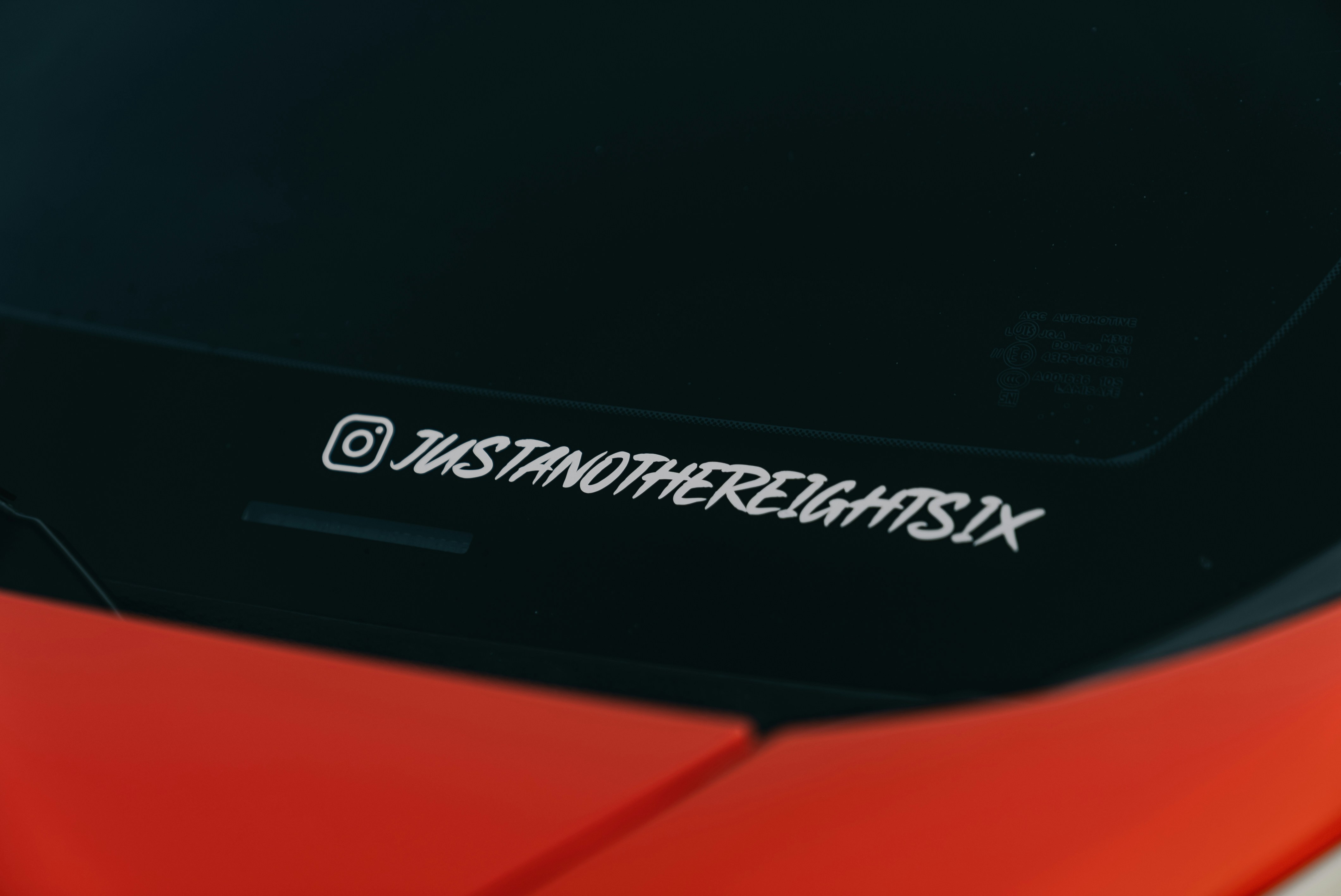 Stickered homage: a close-up of social handle on a glossy red surface