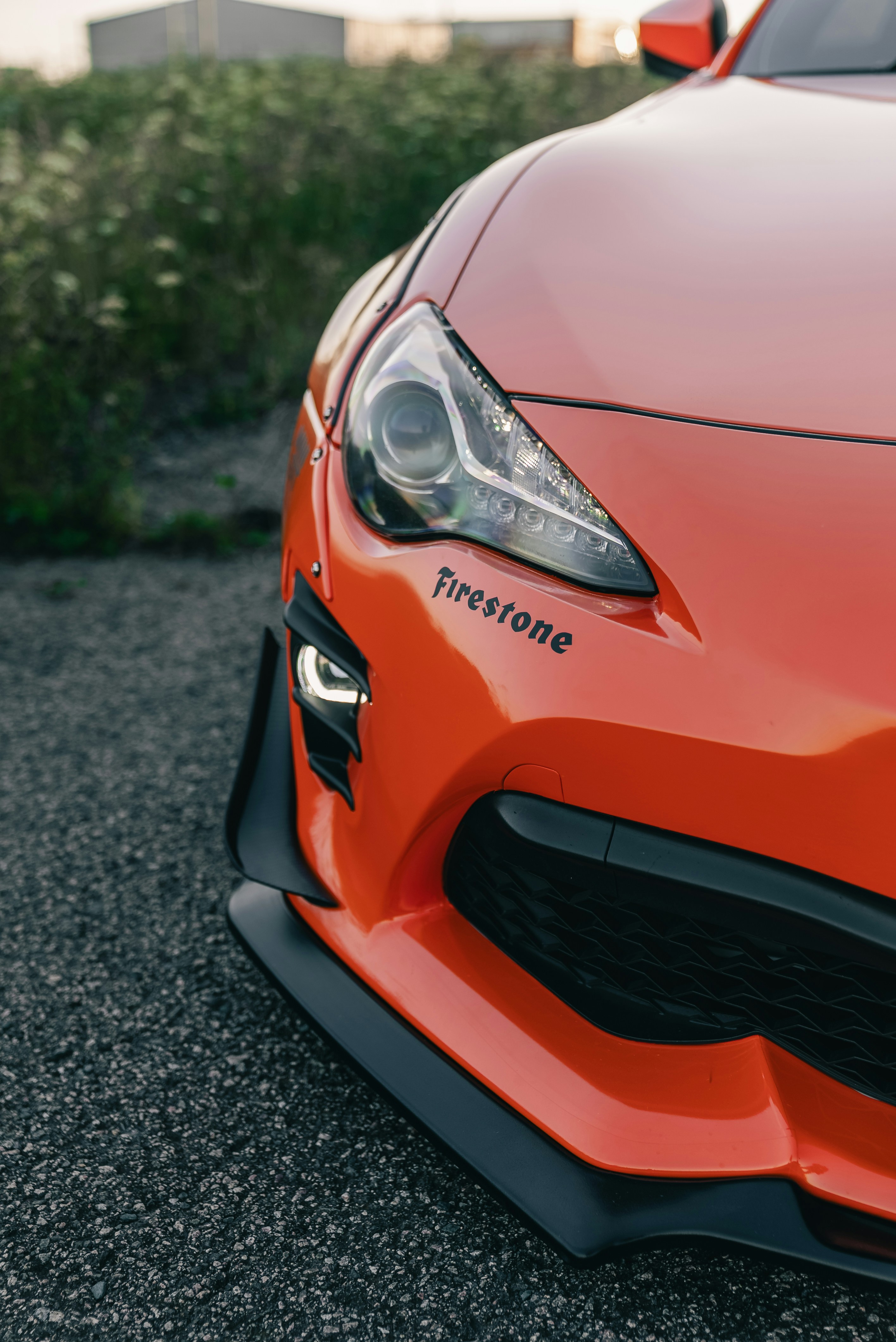 Aggressive orange stance: close-up of a Firestone-branded sports car nose