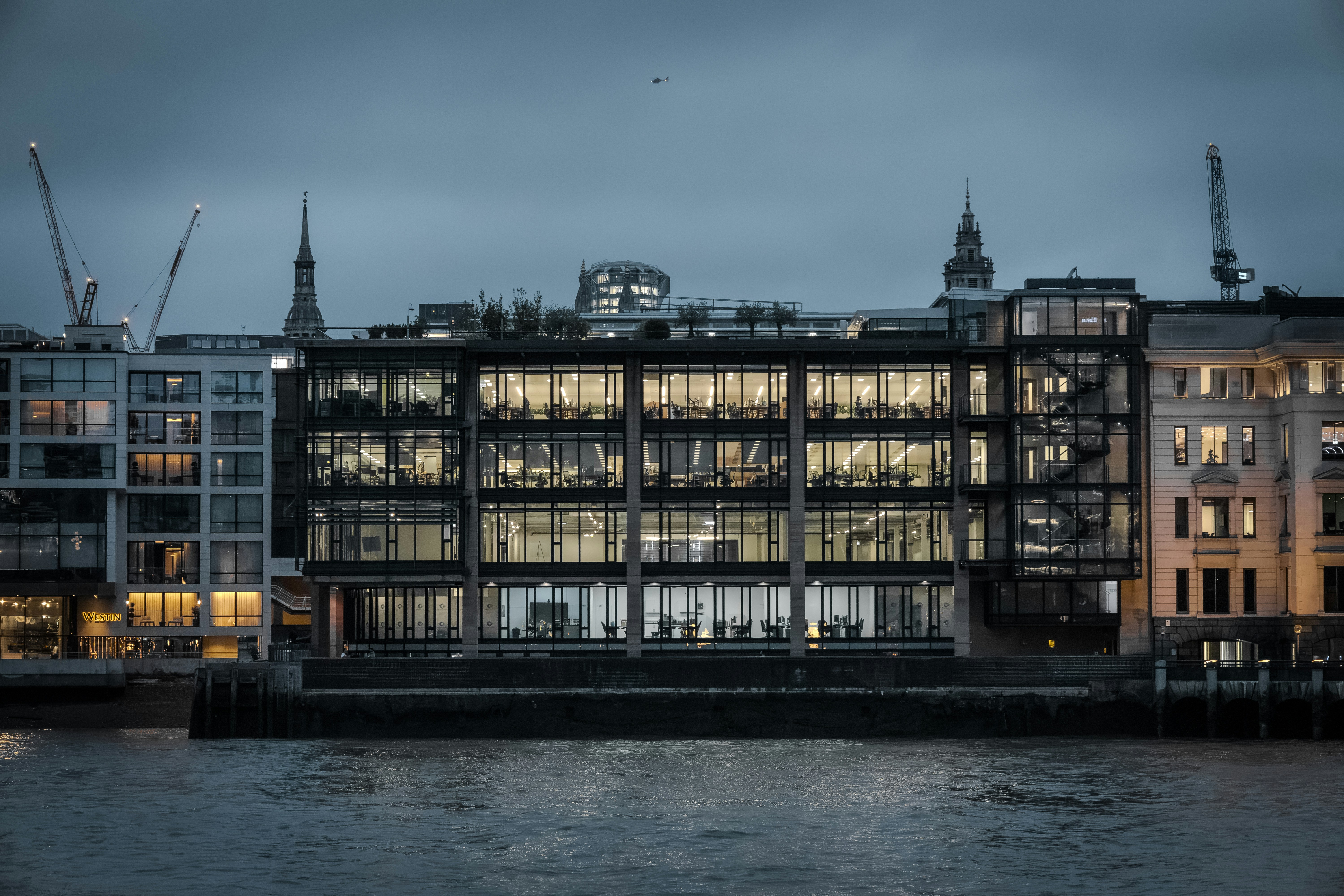 Glass-fronted riverfront office glowing at twilight