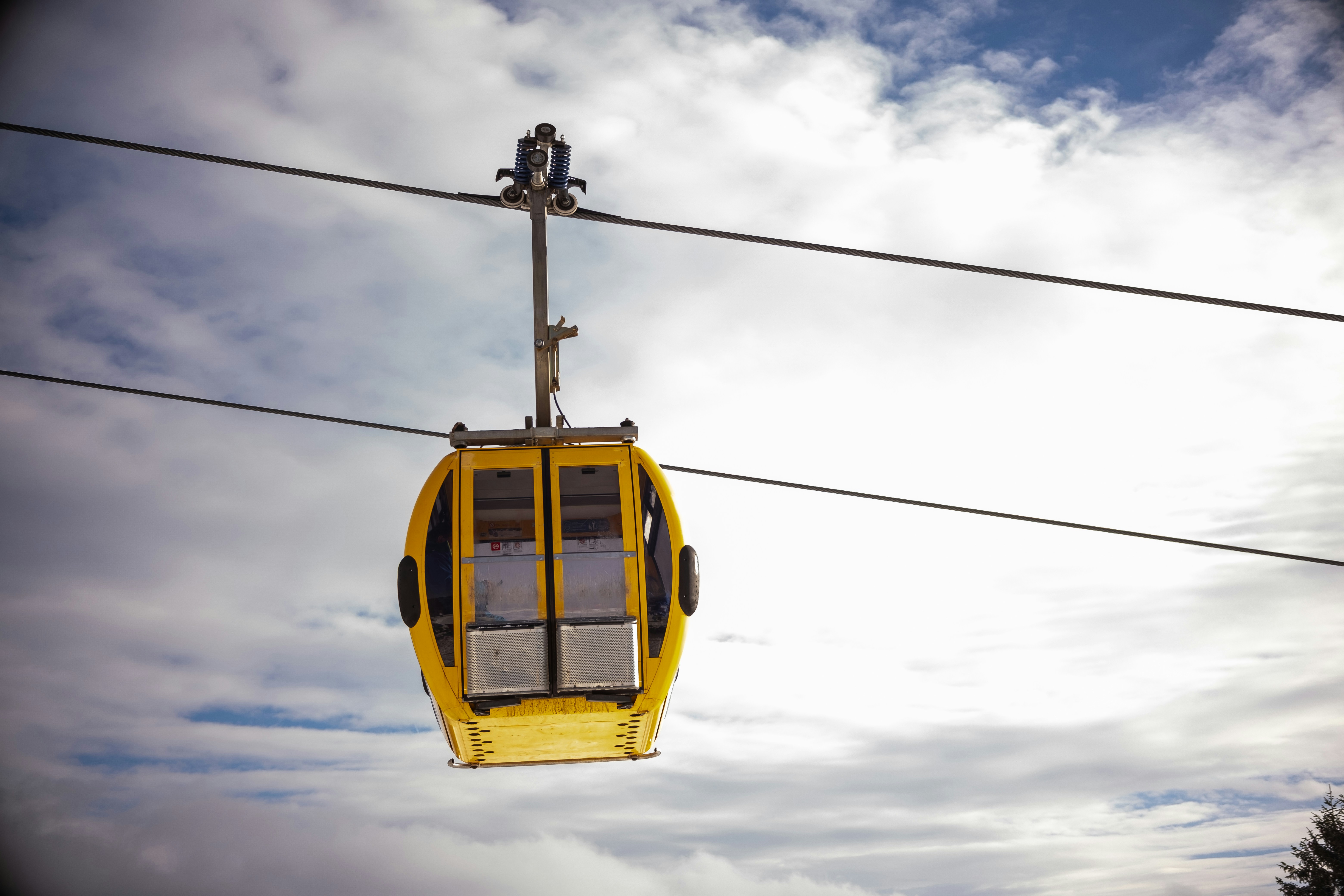 Yellow Cabin in the Sky: A Cable Car Against the Open Cloudscape