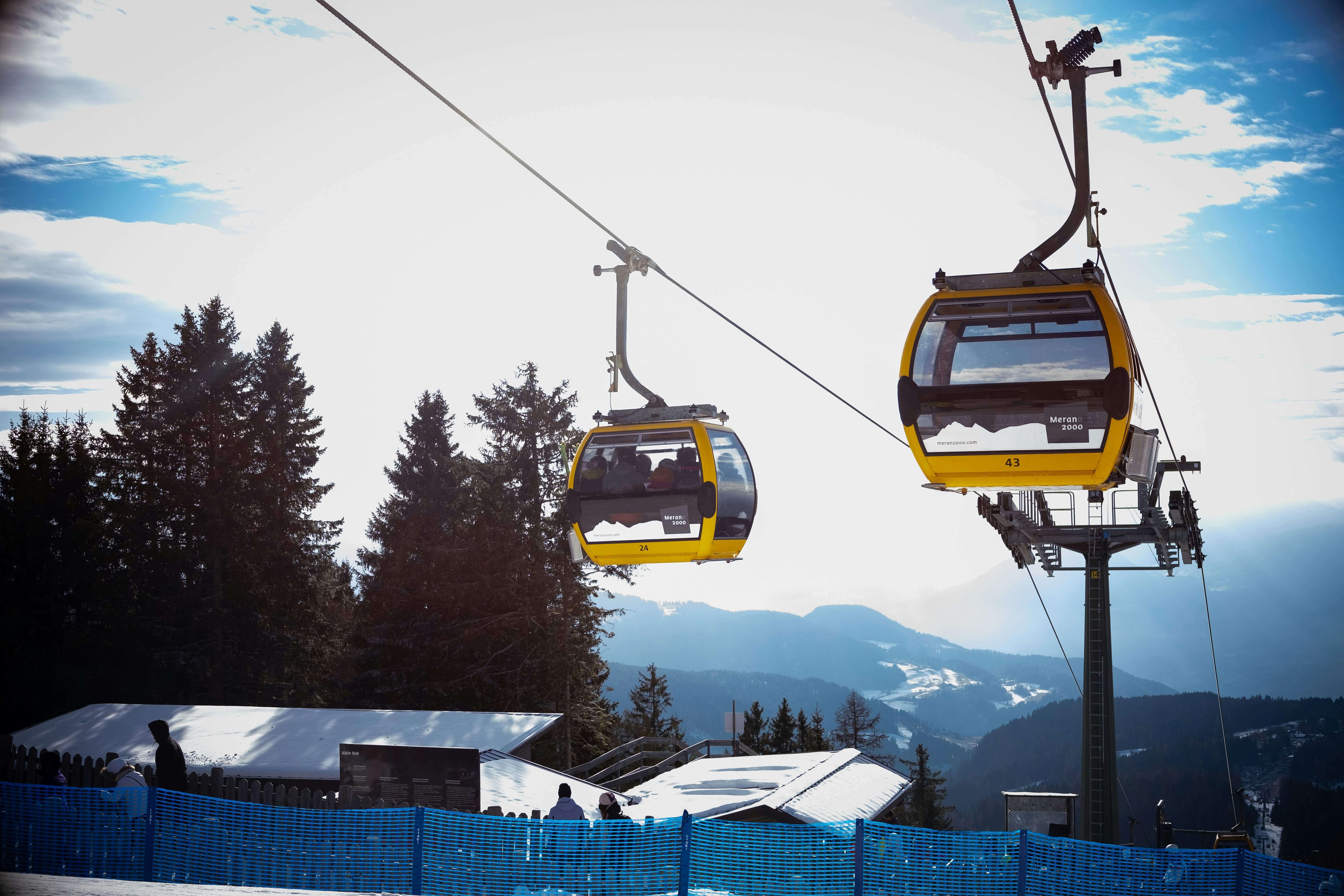 High Altitude Lift Ride: Two Yellow Cabins Soaring Over Snowy Slopes