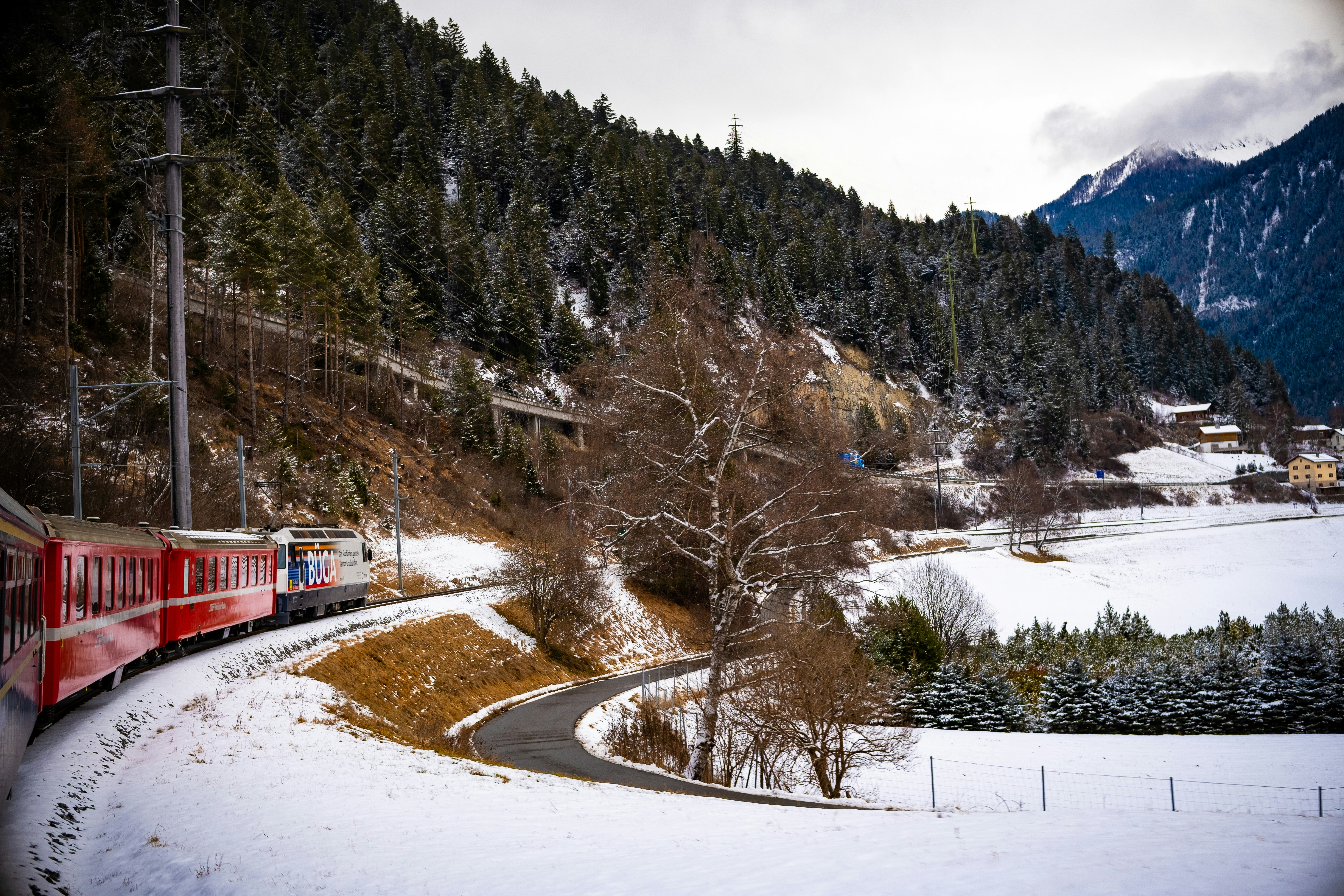 Snow-Swept Mountain Railway: A Red Car Winding Along the Frozen Lake