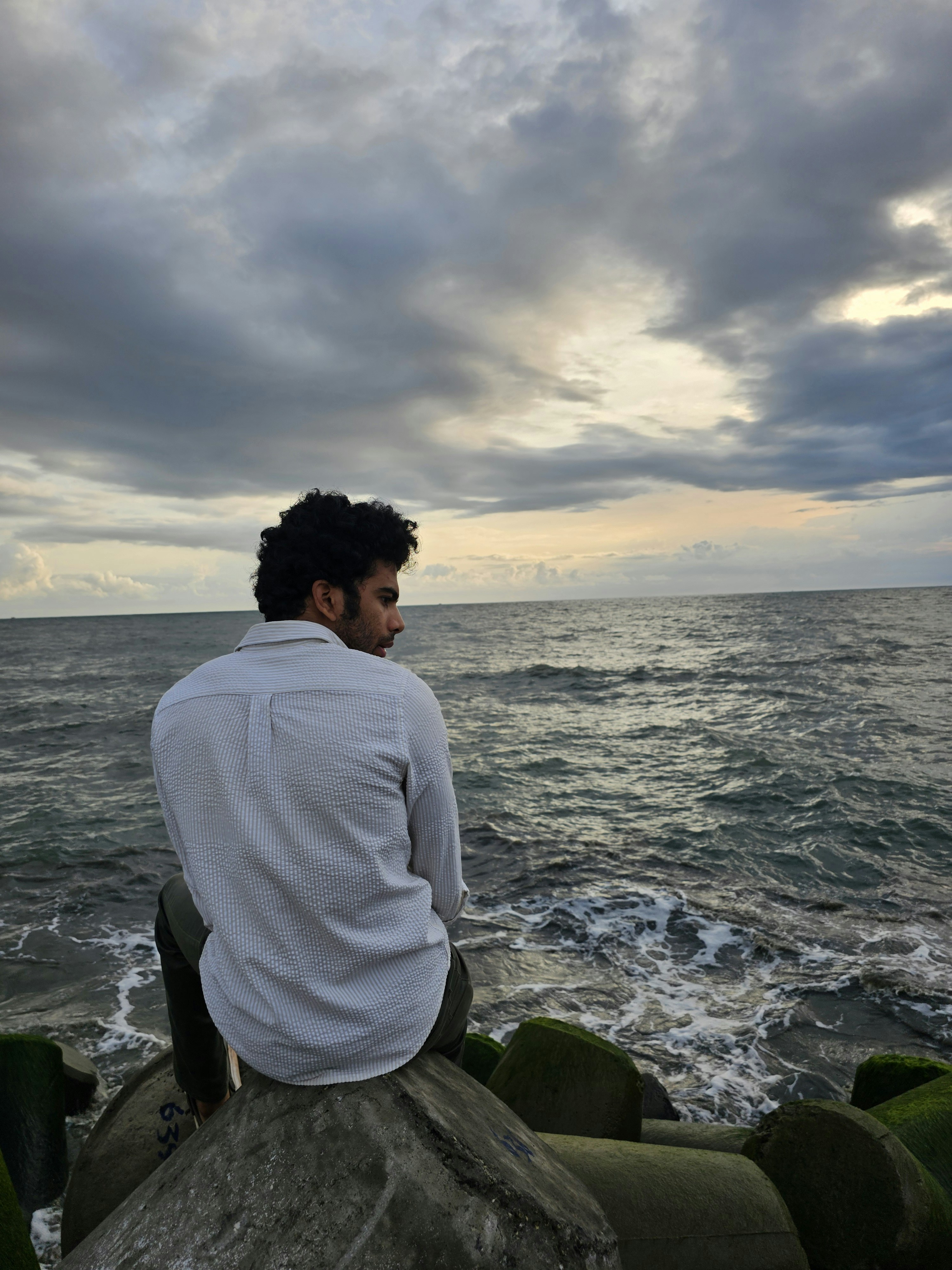 Solitary Pose at the Edge: Man on Sea-Tossed Rocks