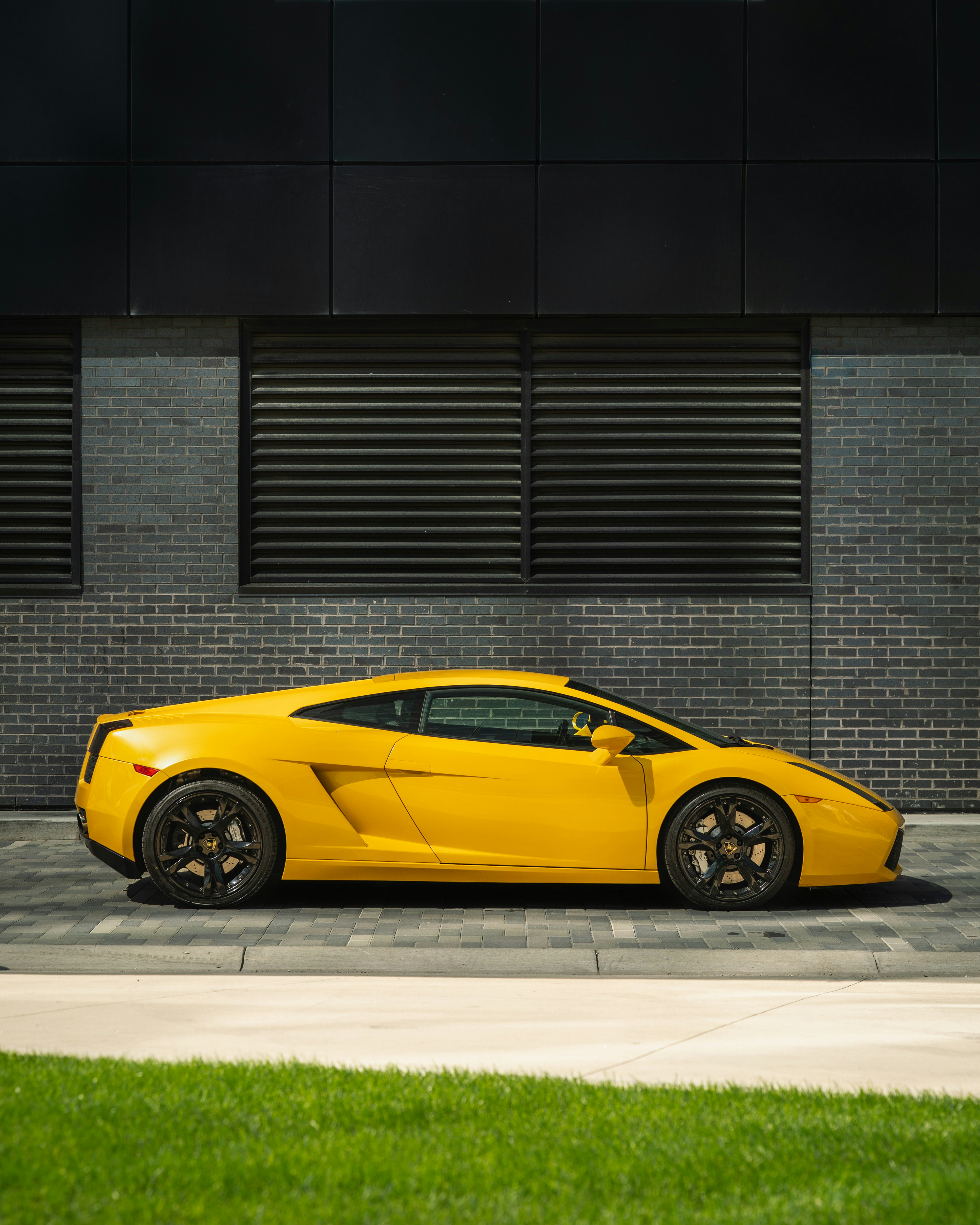 Sunlit Yellow Apex: A Lamborghini Huracán Resting by the Brick Wall