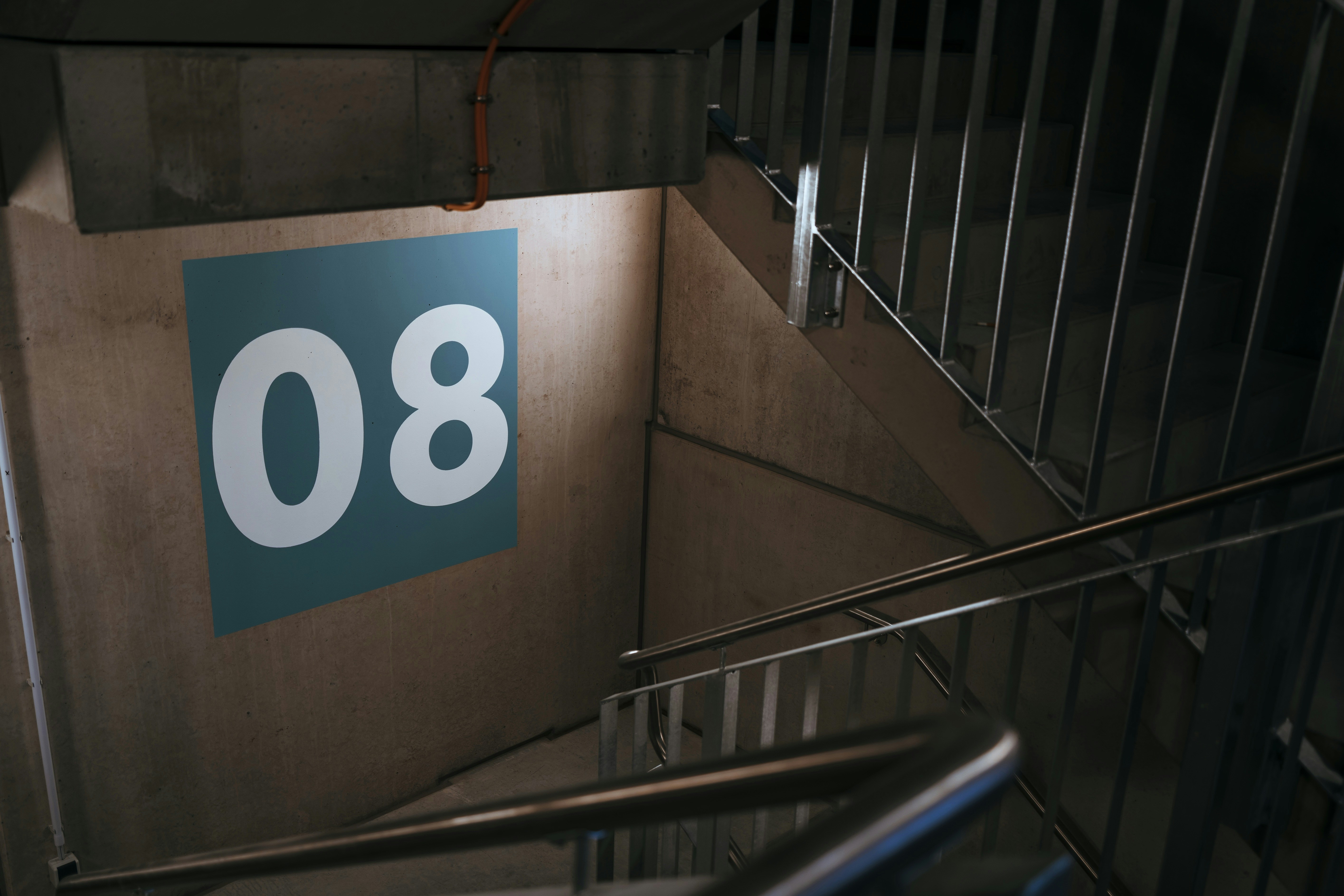 Exit Sign Beyond the Railing: A Quiet Stairwell at Floor Eight