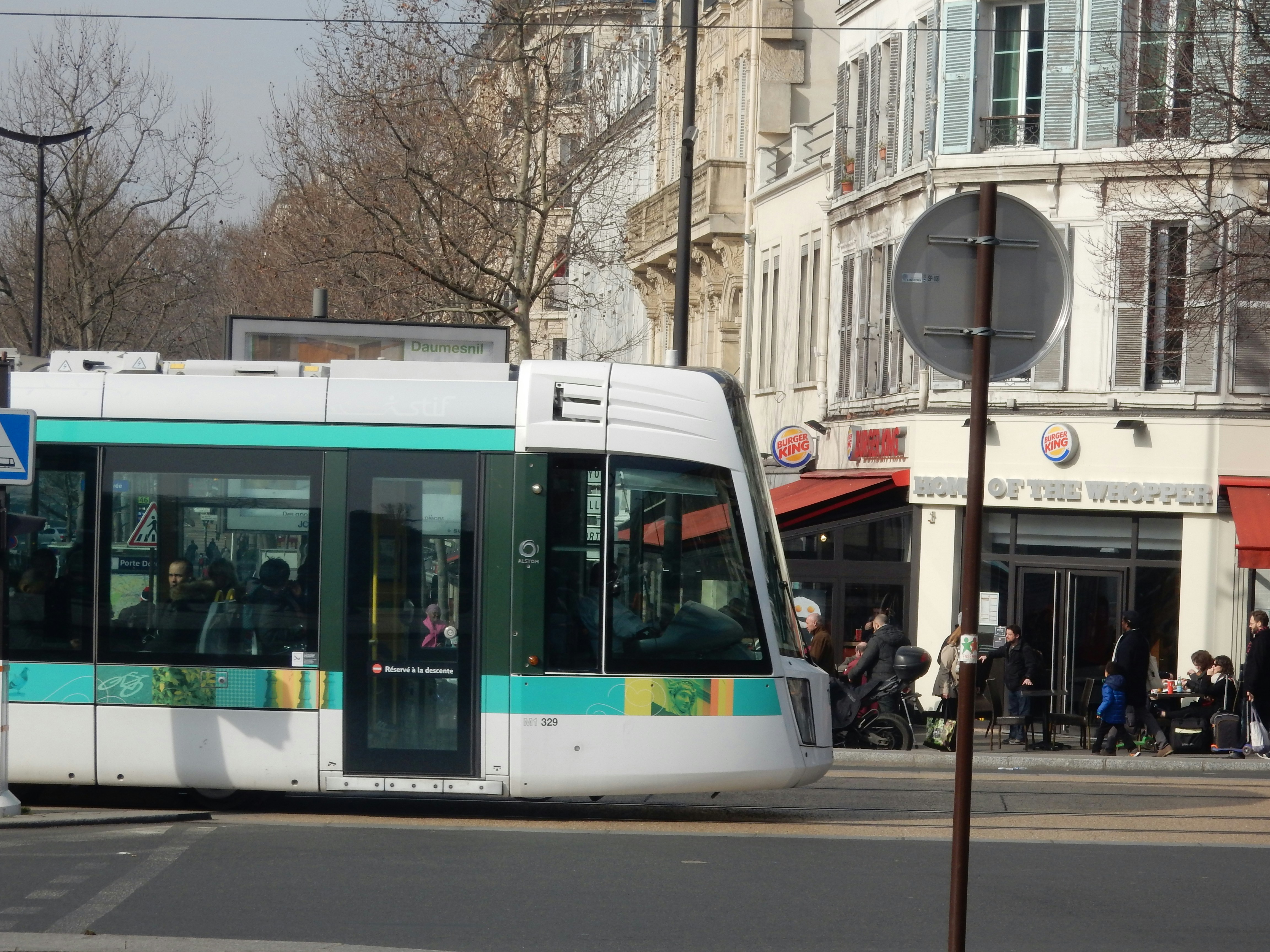 Urban Tranquility in Motion: A Tram Glides Past Cafés