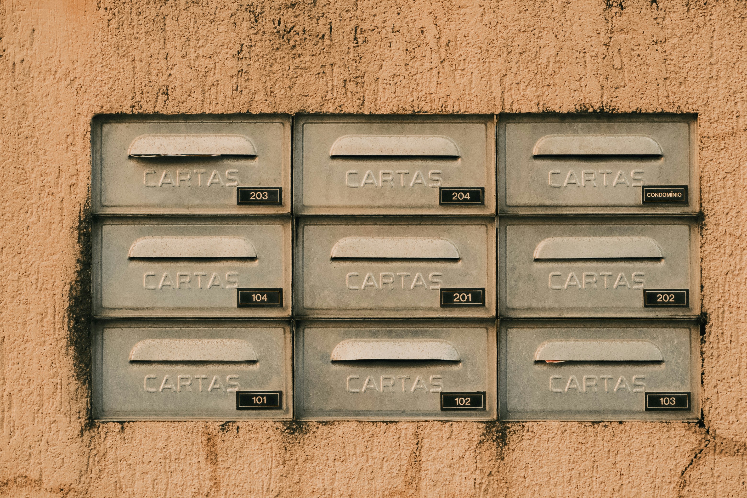 Row of Weathered Mailboxes on a Sunlit Brick Wall