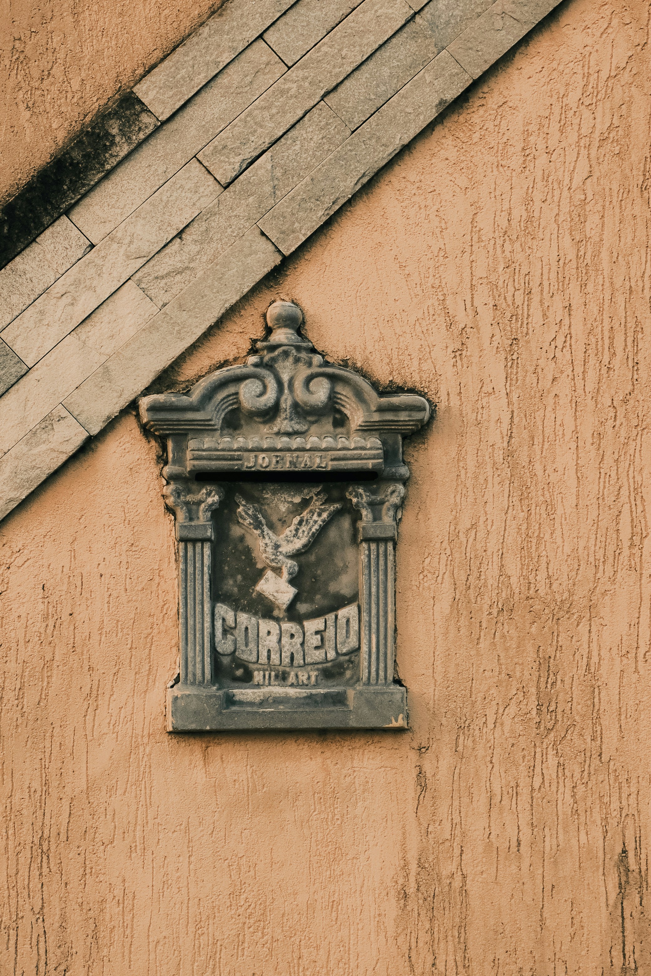 Weathered Crest: An Ornate Plaque on Sunlit Clay Wall