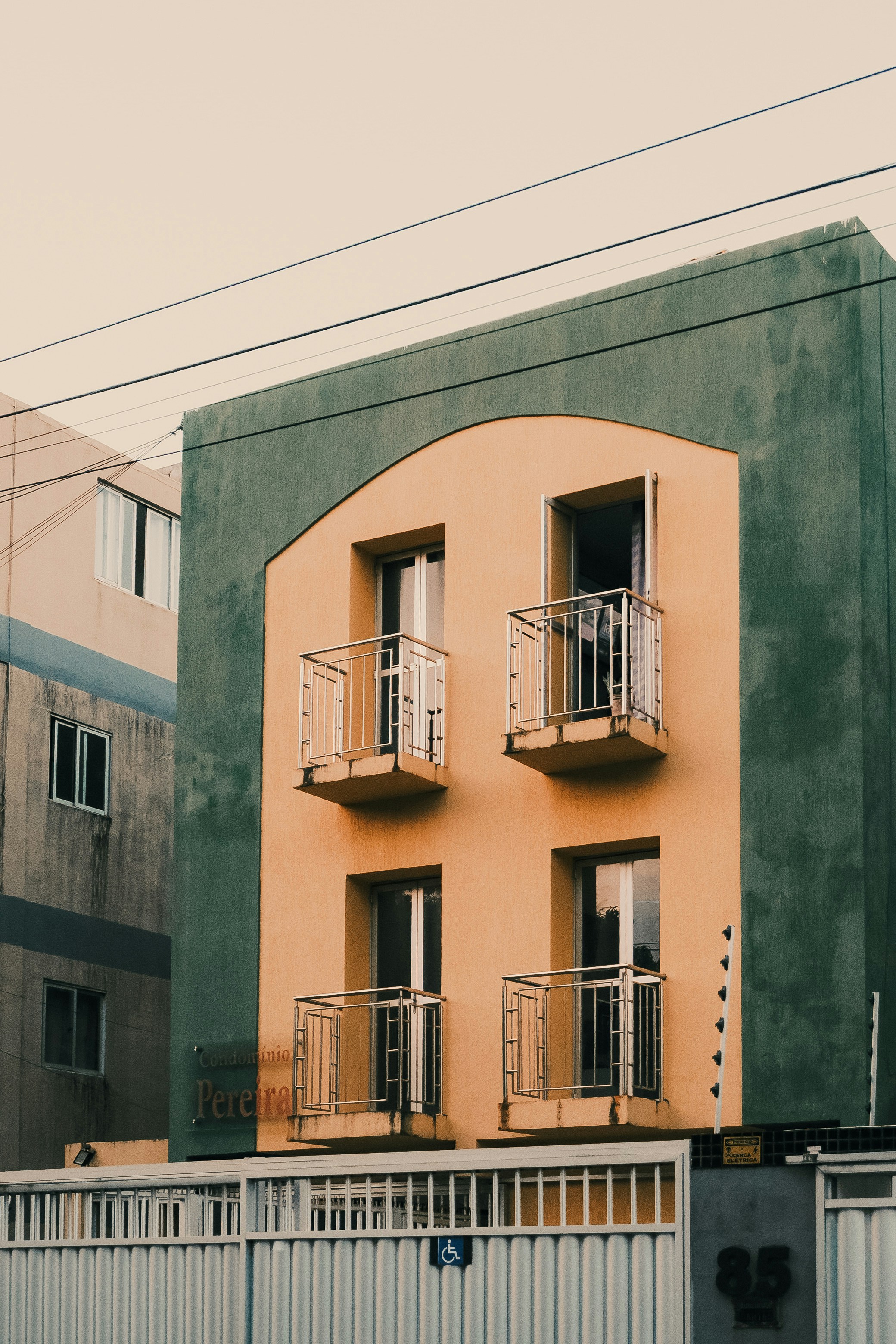 Facade in Warm Light: A Peach-toned Building with Green Accents