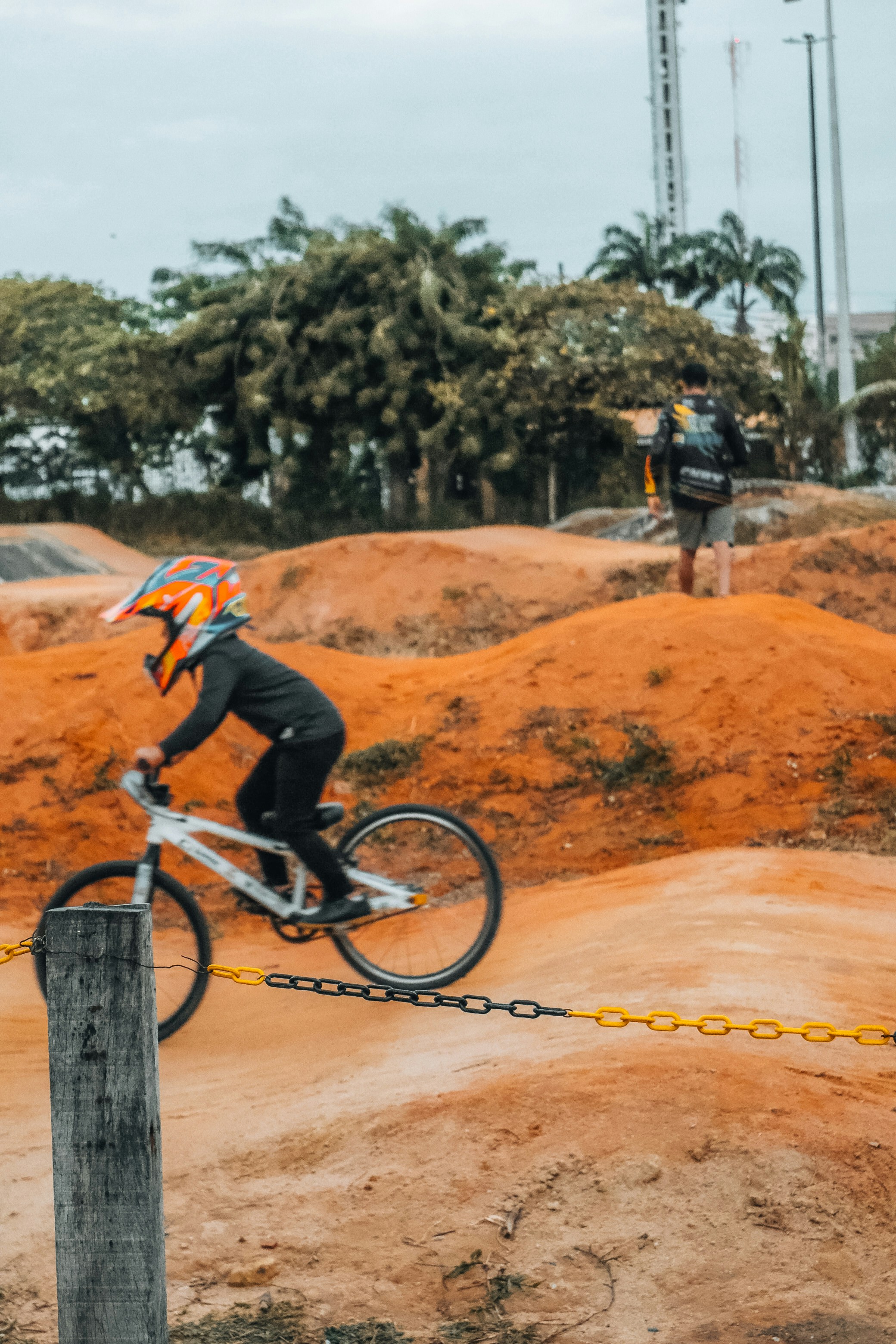 Riders and Track in Orange Dust Under Cloudy Skies