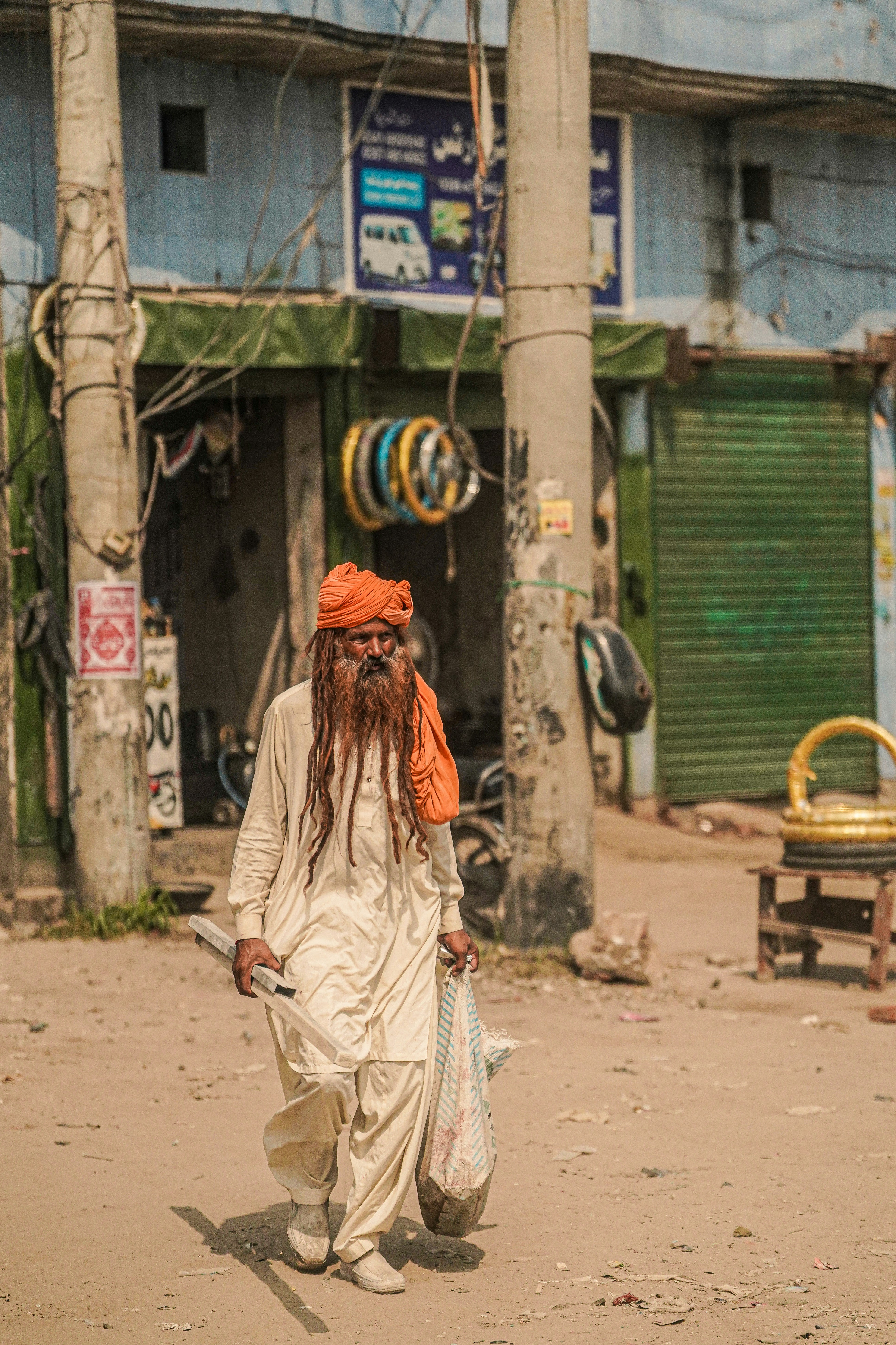Orange Turban, Cream Attire: A Wanderer Crosses a Dusty Street