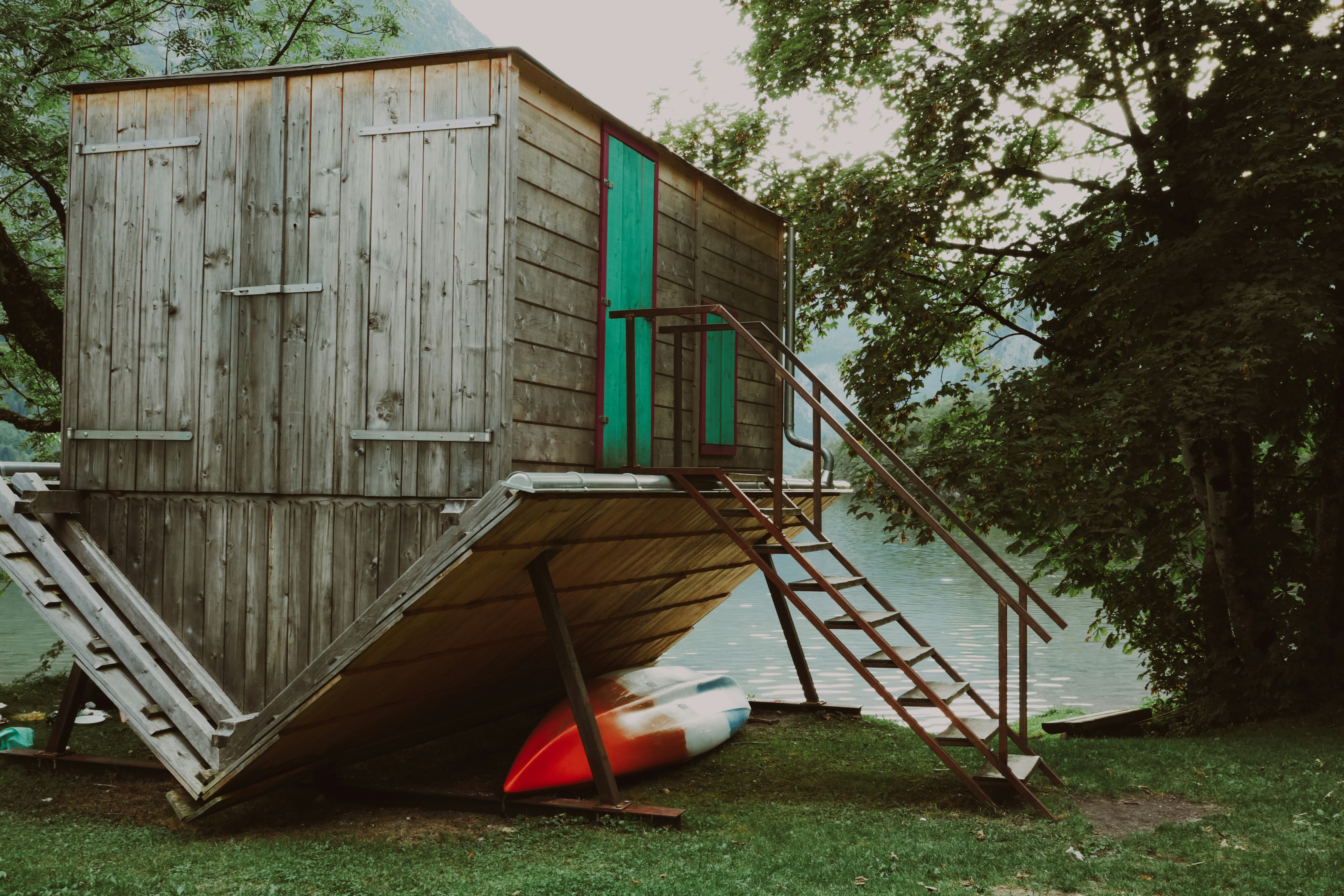 Lakeside A-frame on stilts: timber cabin by the water with a red kayak peeking underneath