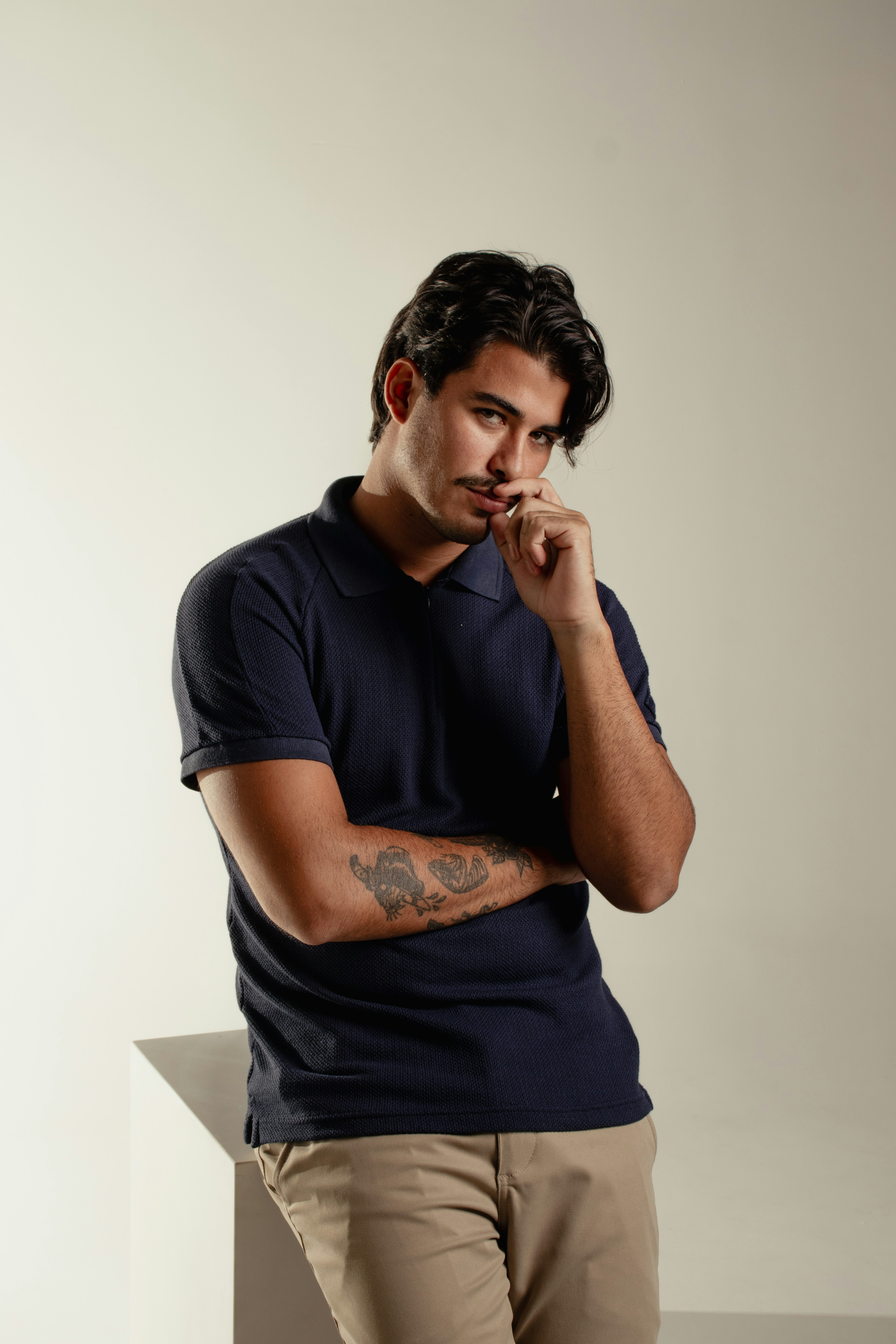  contemplative portrait: sleeves, shadow, and a steel-blue polo