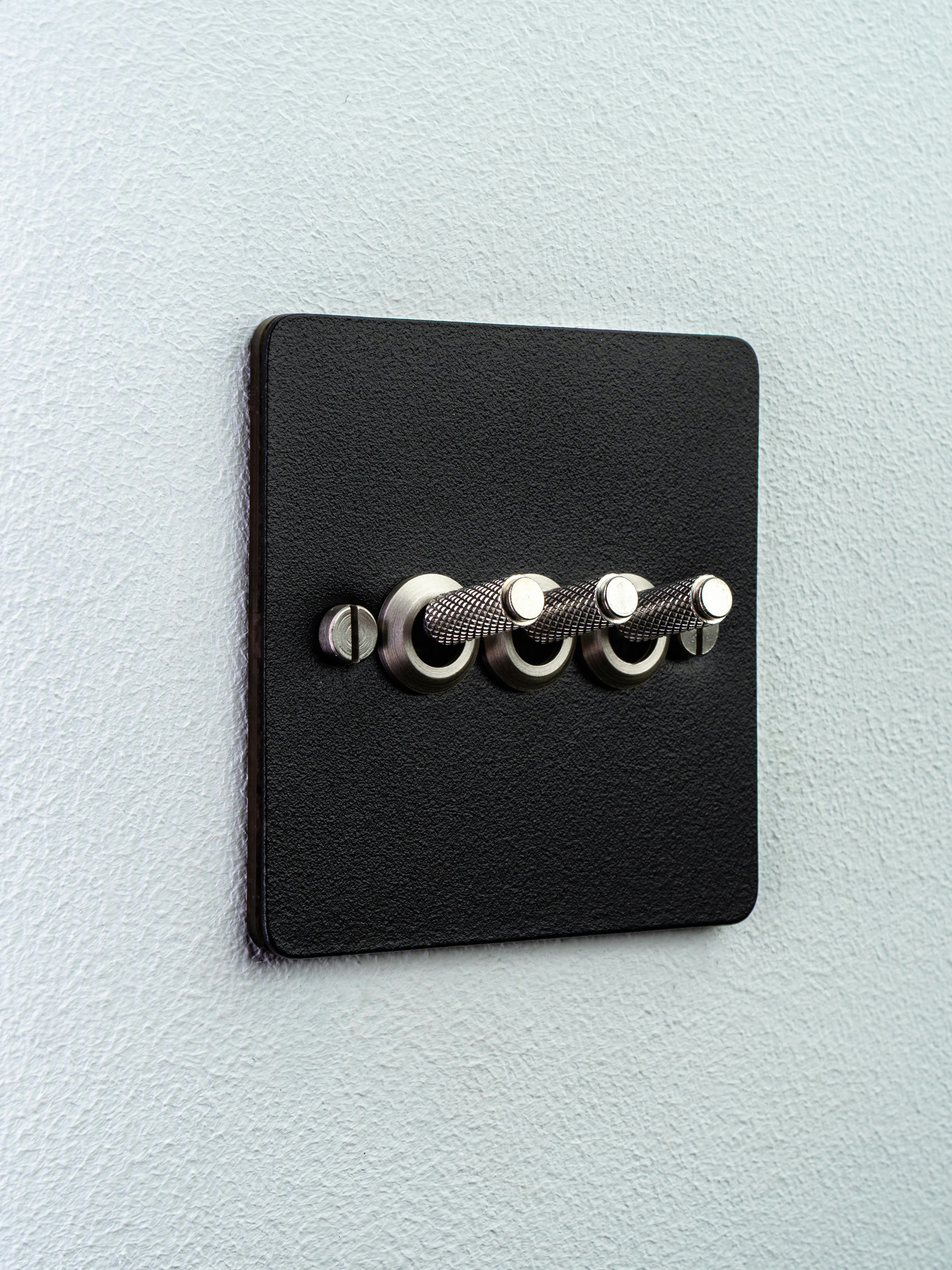 Industrial Key: A Close-Up of a Metal Toggle Panel on Pale Blue Wall