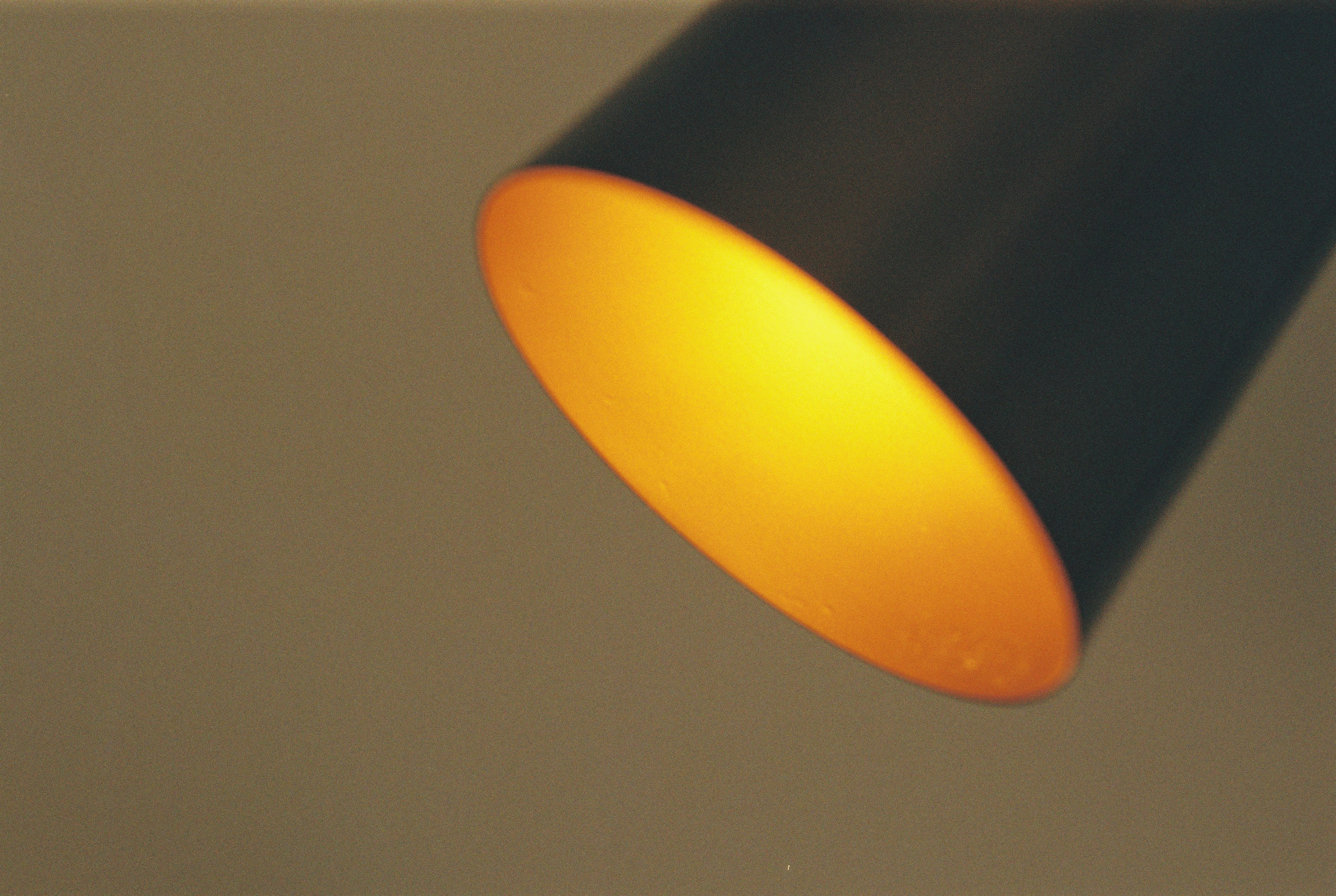 Warm Halo: A close-up of a tilted lamp shade glowing amber