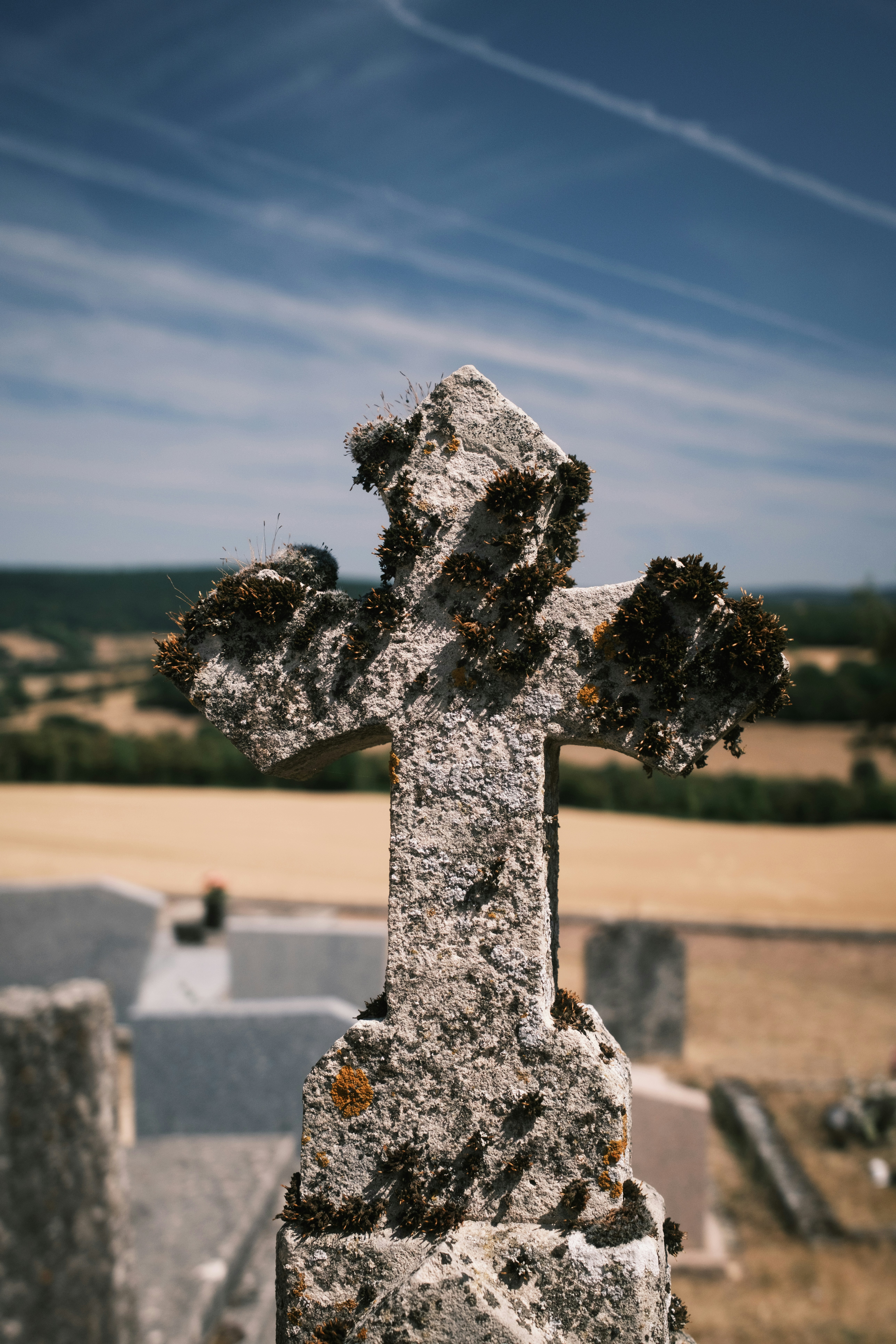 Weathered stone cross: a lone grave marker under a wide rural sky
