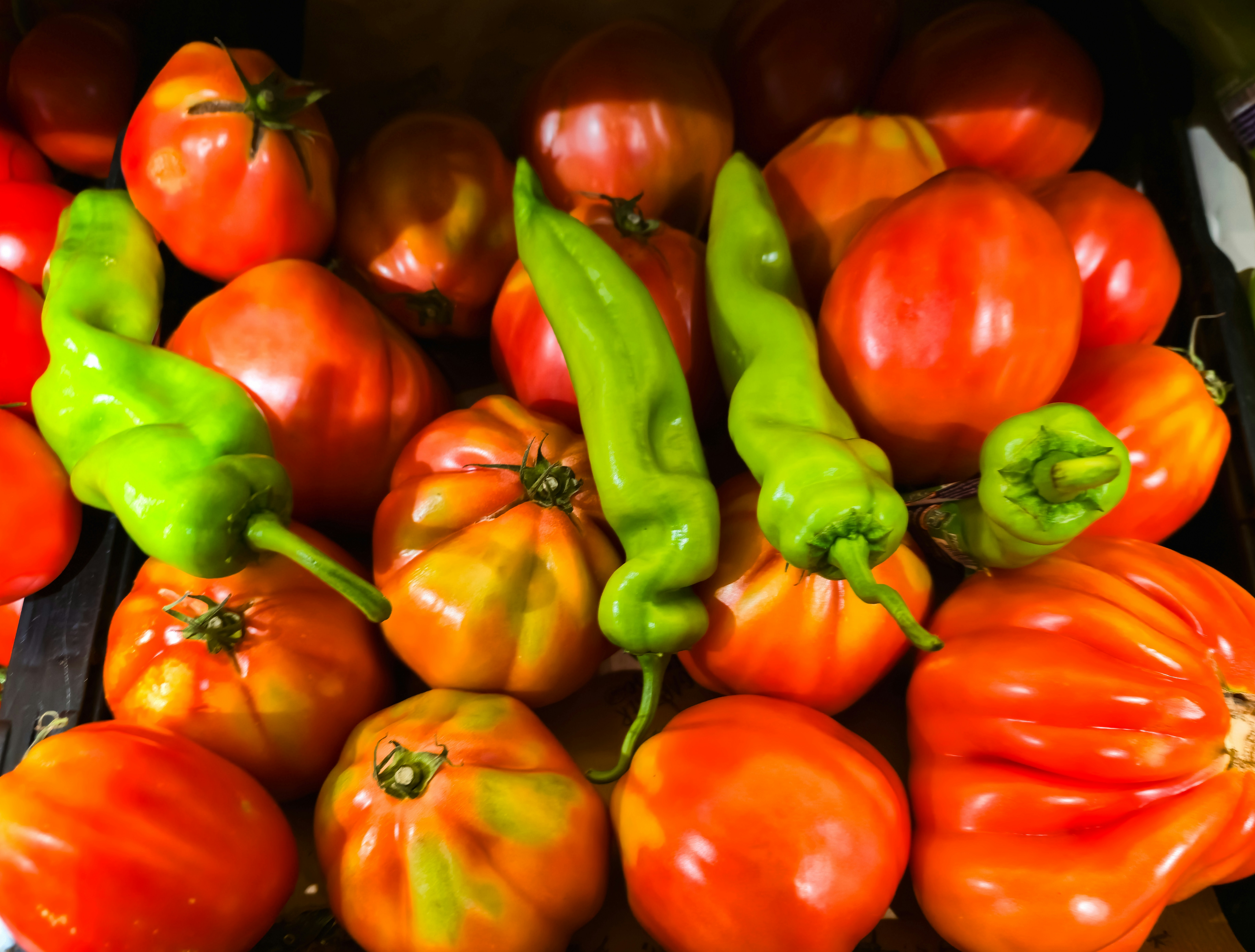 Bright harvest: a crate of glossy orange tomatoes with a few lime-green peppers