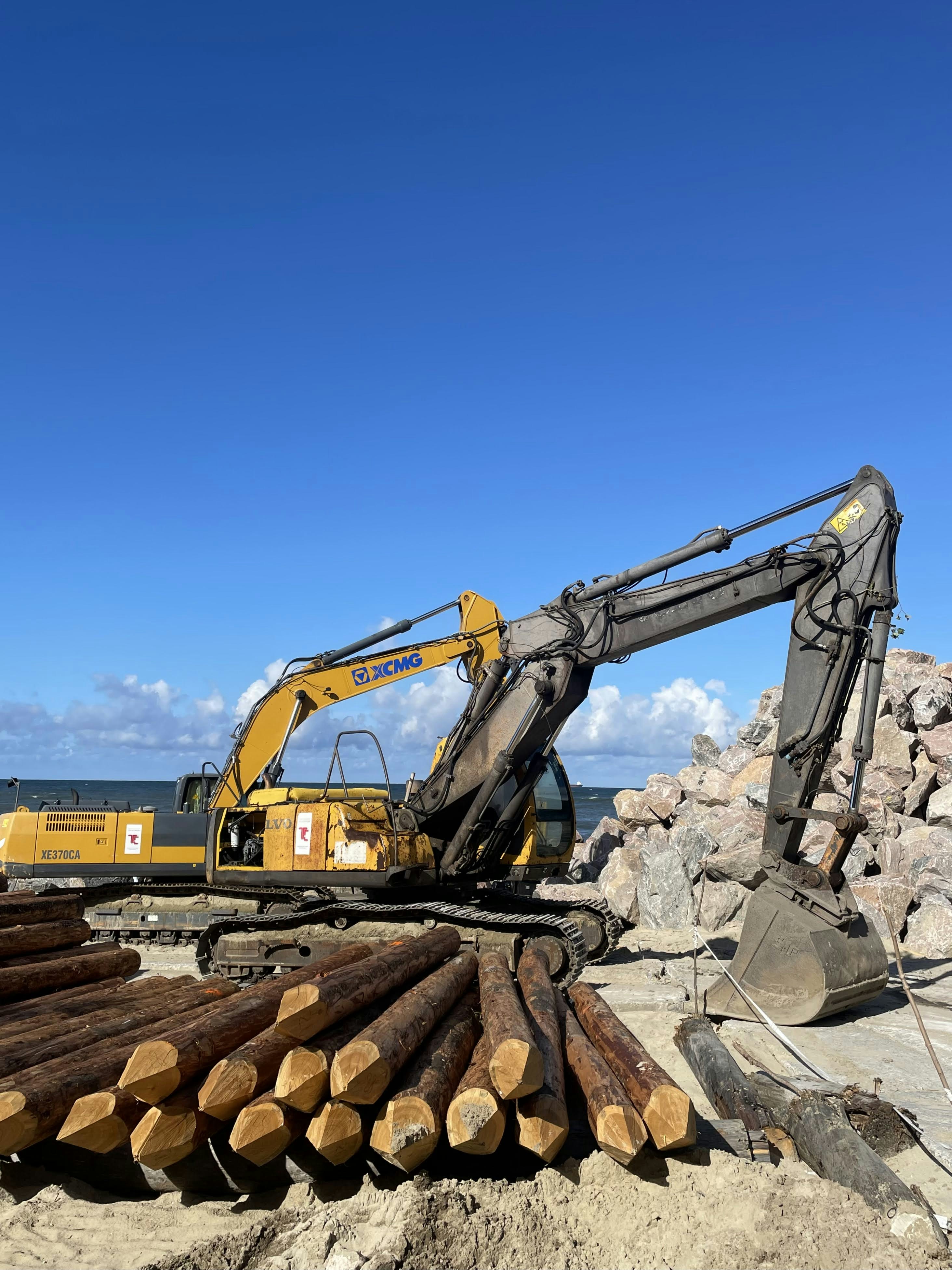 Yellow Excavator at Shoreline Quarry with Stacked Timber
