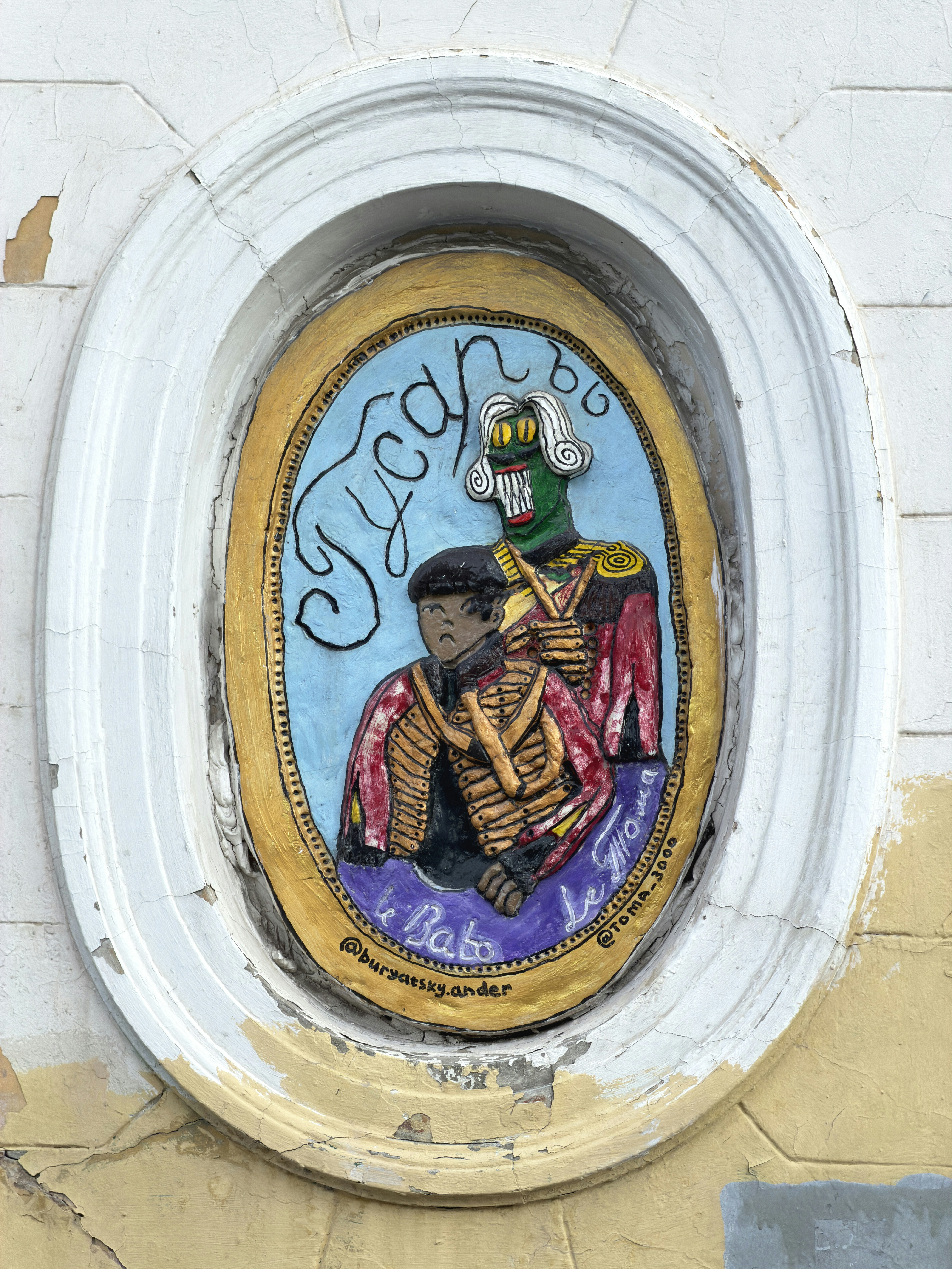 Oval mural within a weathered wall: a stylized figure and companion set in a blue and gold frame
