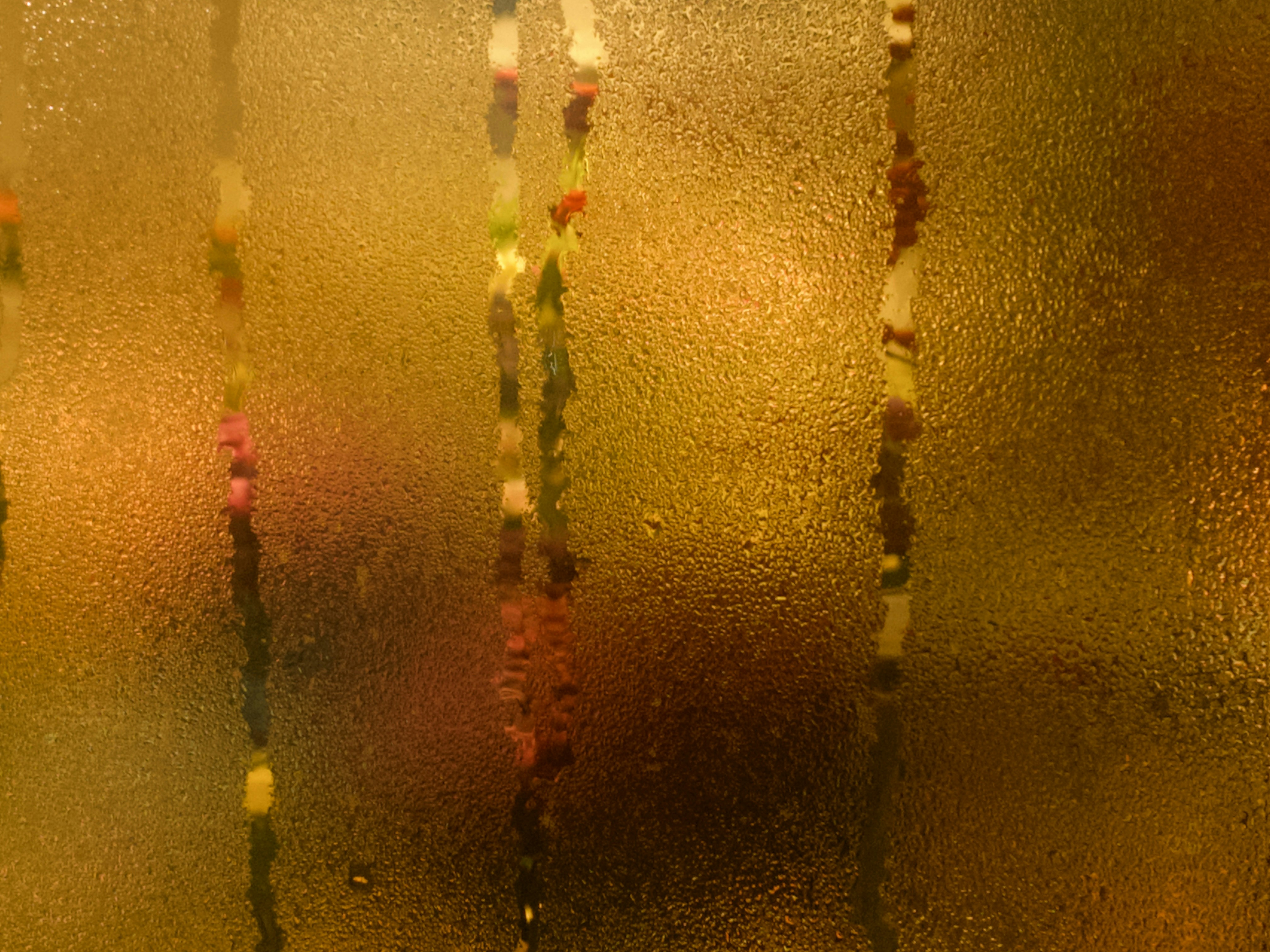 Condensation droplets on a glass surface with warm golden light and blurred colors