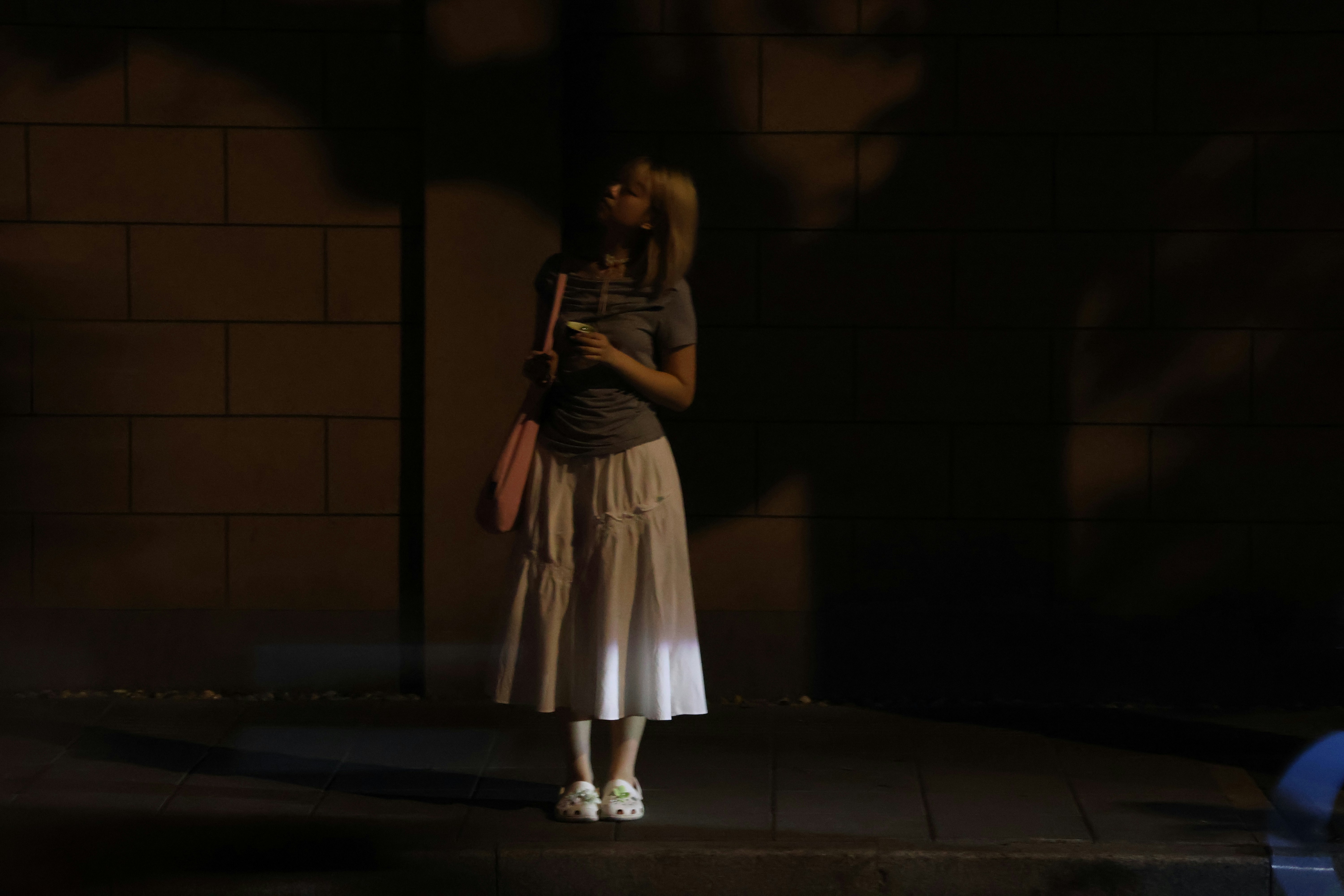 Streetlight Solitude: A Woman in Shadow Under a Quiet City Night
