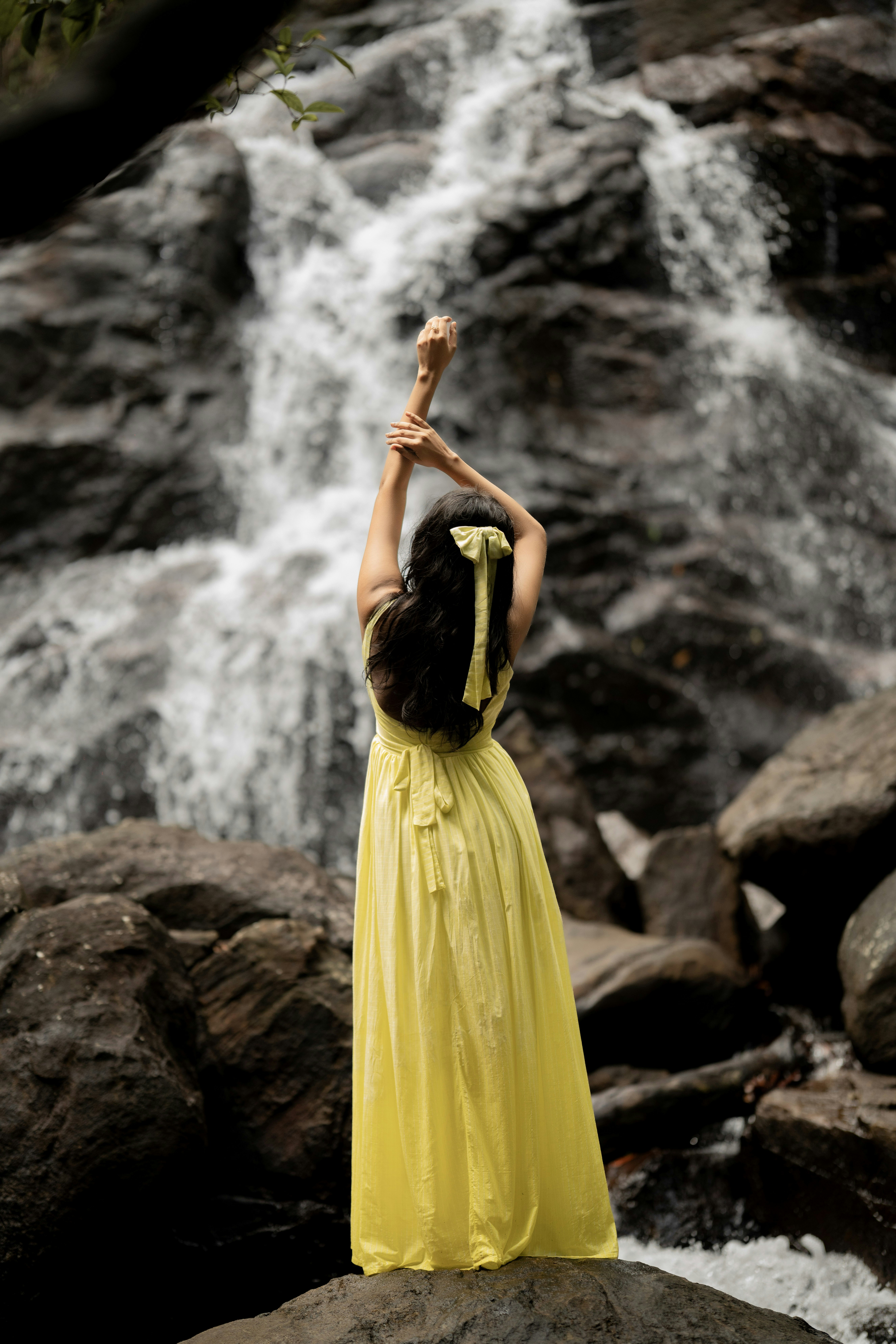 Yellow dress beneath a cascading waterfall