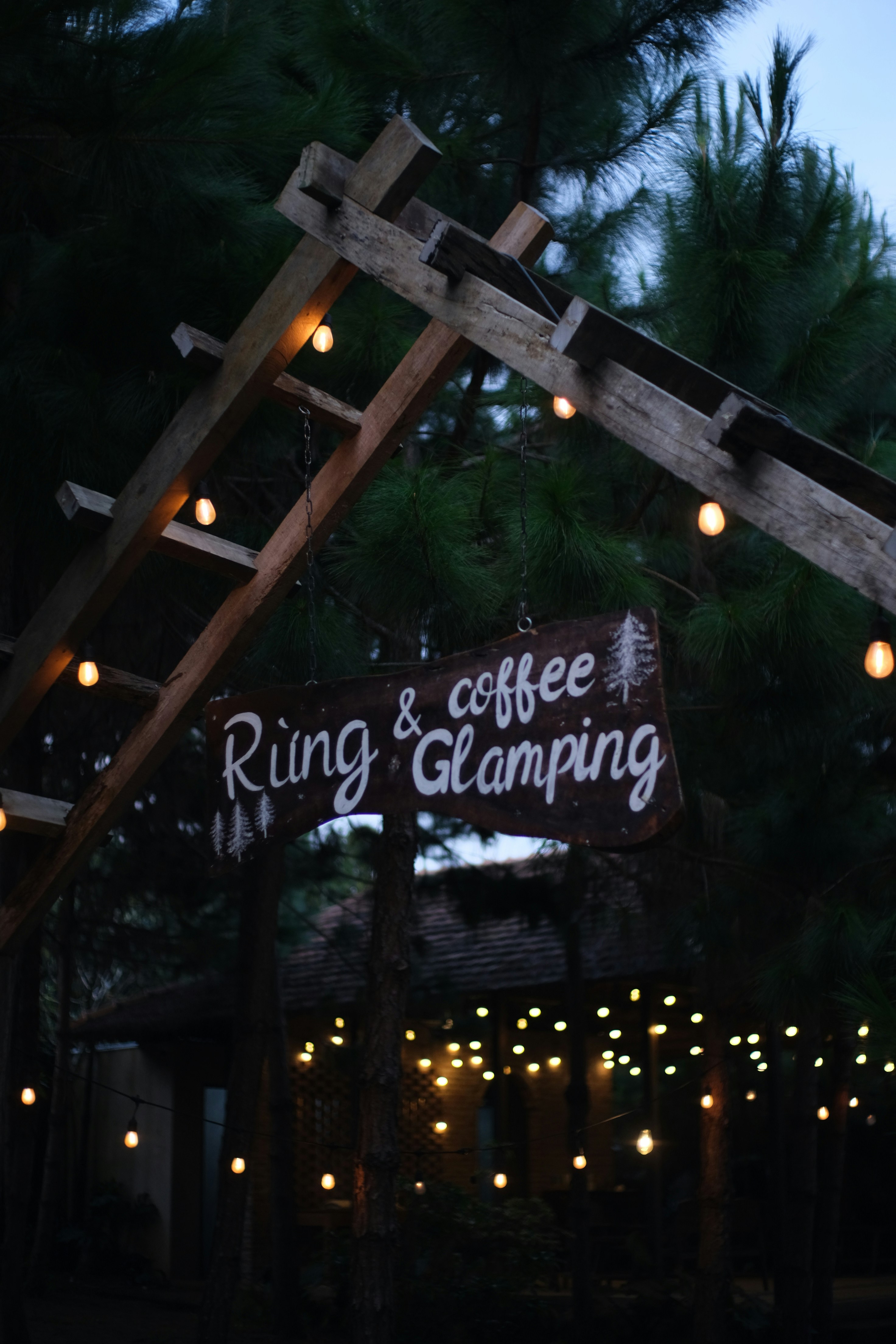 Twinkling Archway of Warm Light Over a Cozy Ring & Coffee Glamping Sign