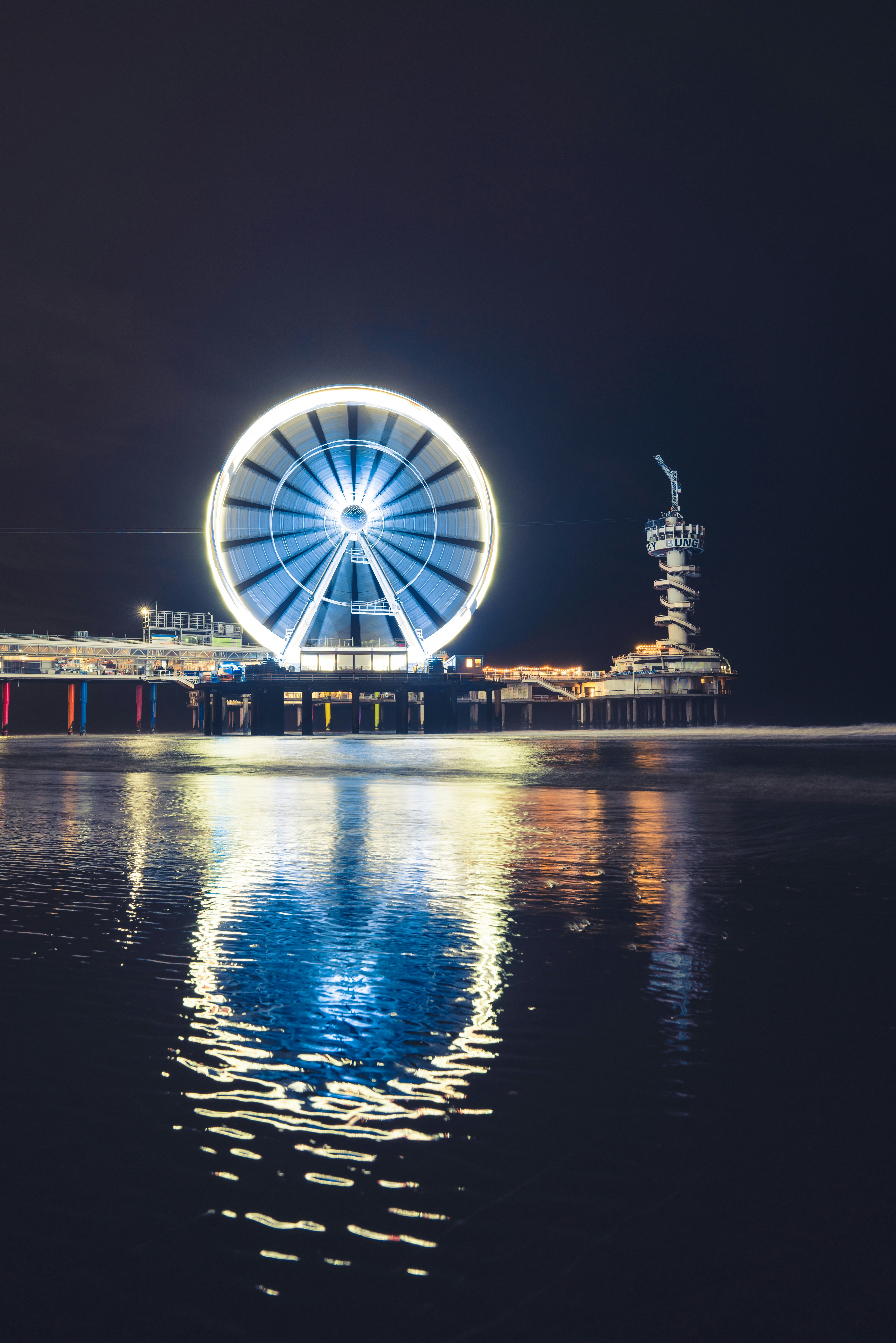 Luminous Wheel over Calm Waters at Midnight Pier