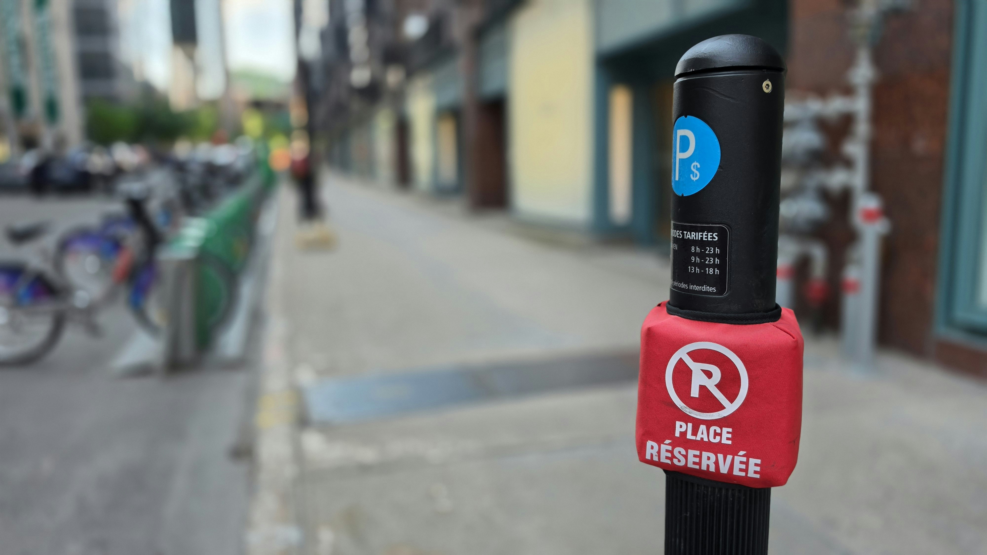 Urban Spotlight: Reserved Sign and Red Post Amid Quiet Street