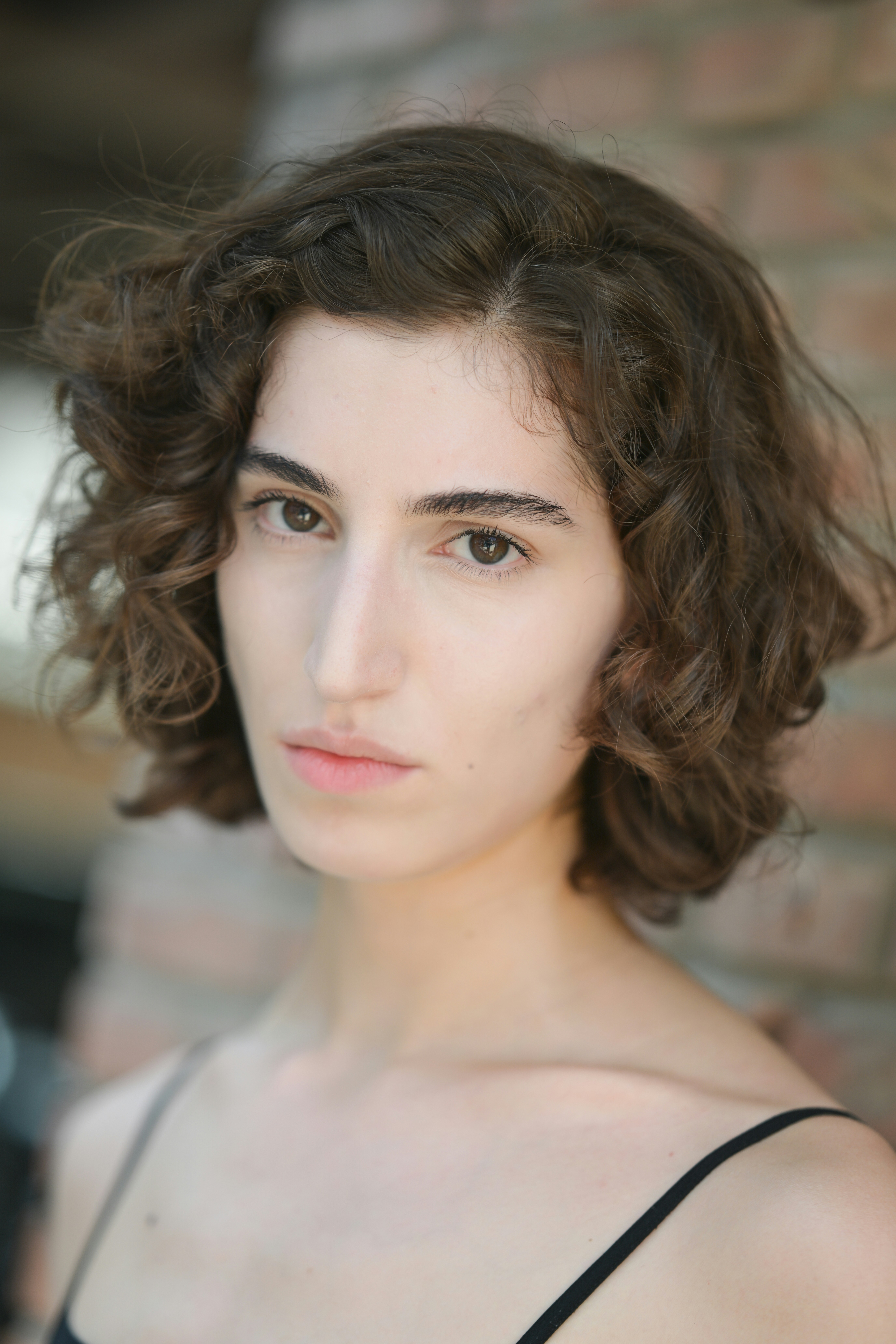 Portrait in Soft Focus: A Quiet Gaze against a Brick Backdrop