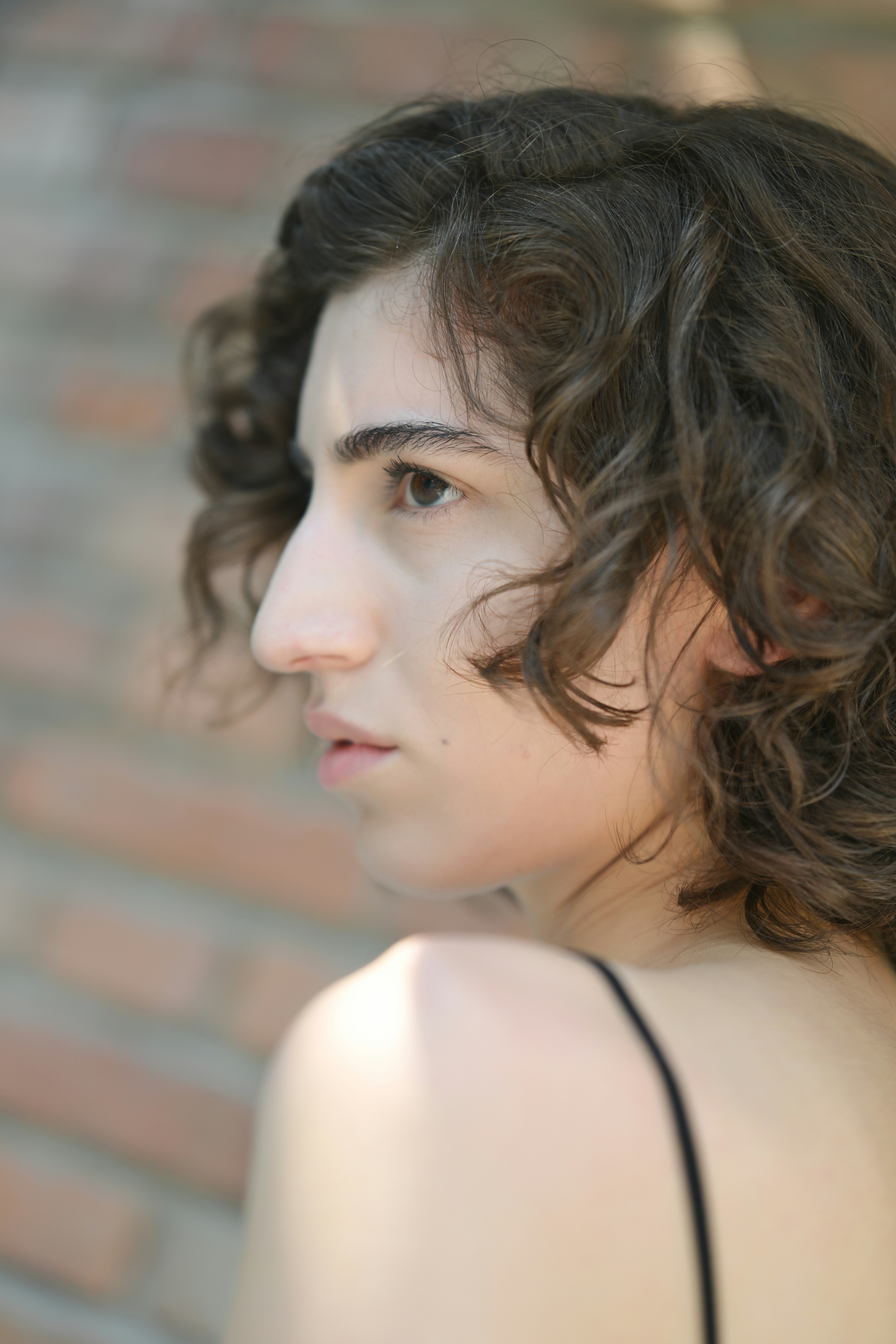 Portrait in Soft Light: A Side-Profile Against Brick
