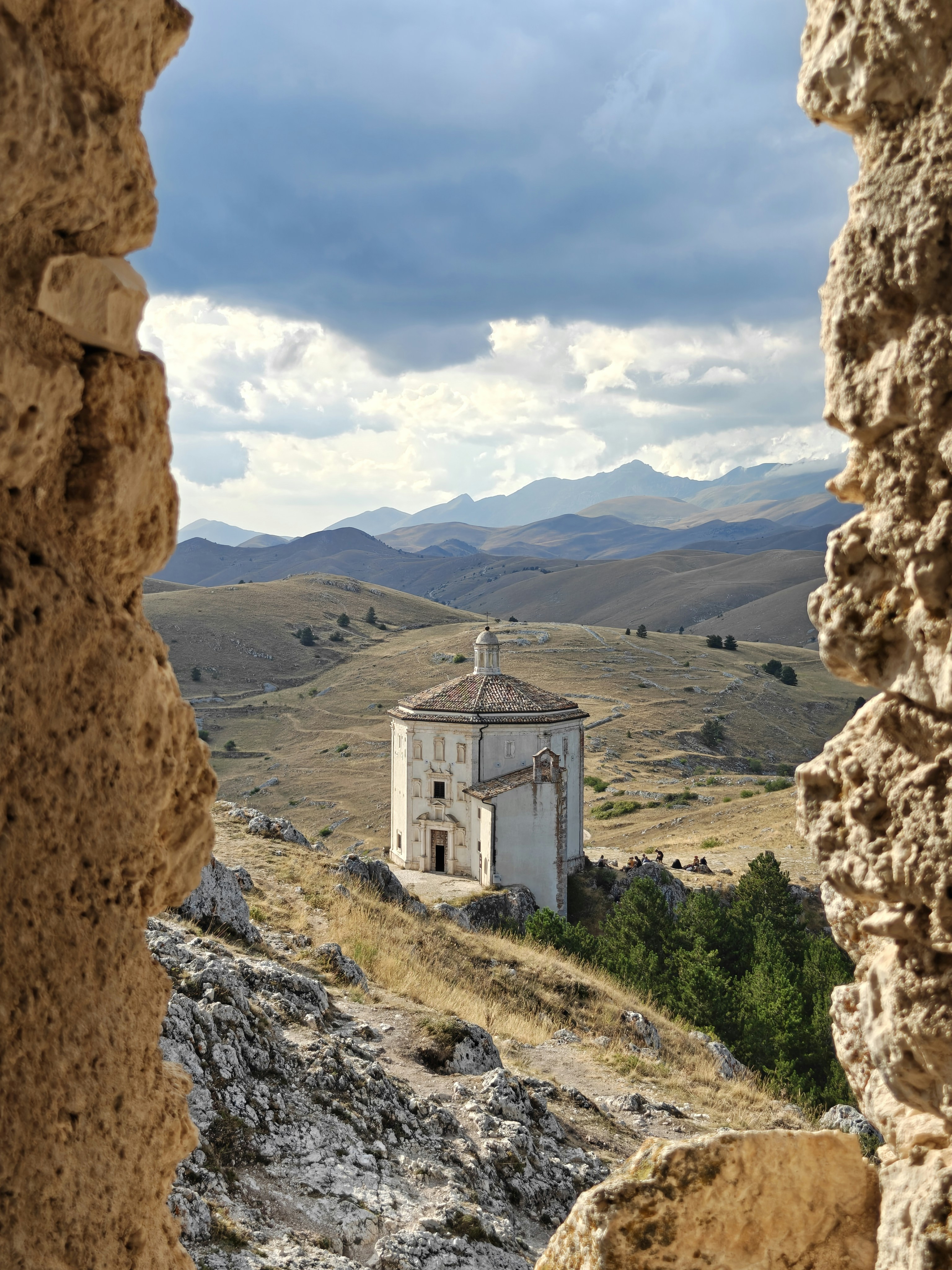 island chapel in a sunlit valley framed by rugged ruins