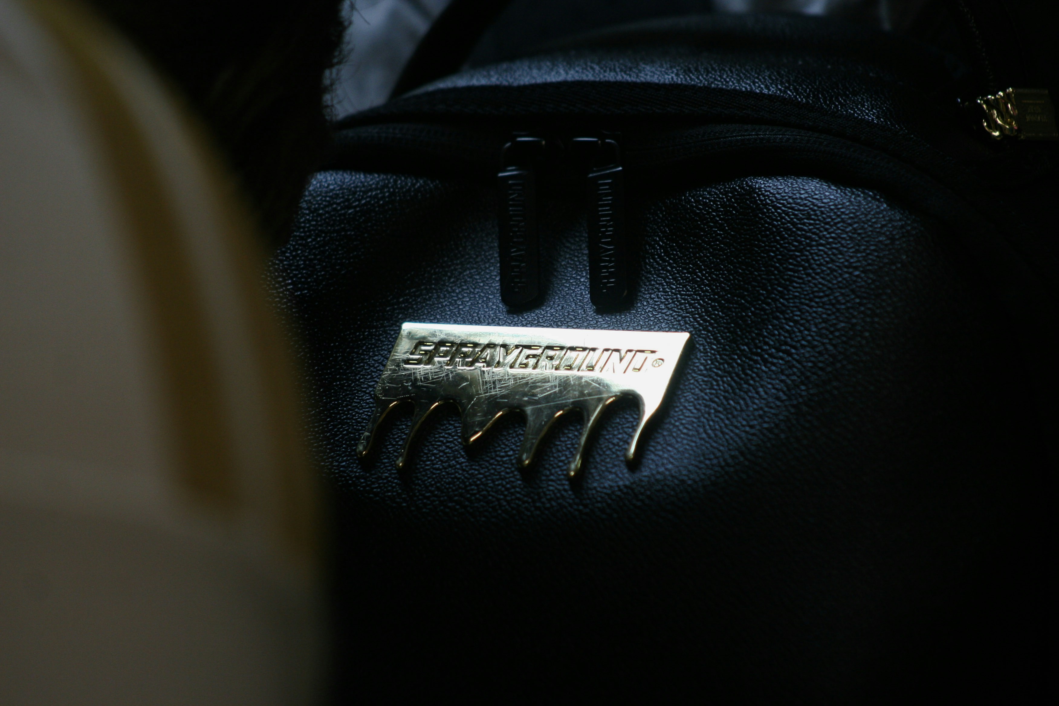 Leather Backpack Emblem: a metallic logo nestled in shadowed texture