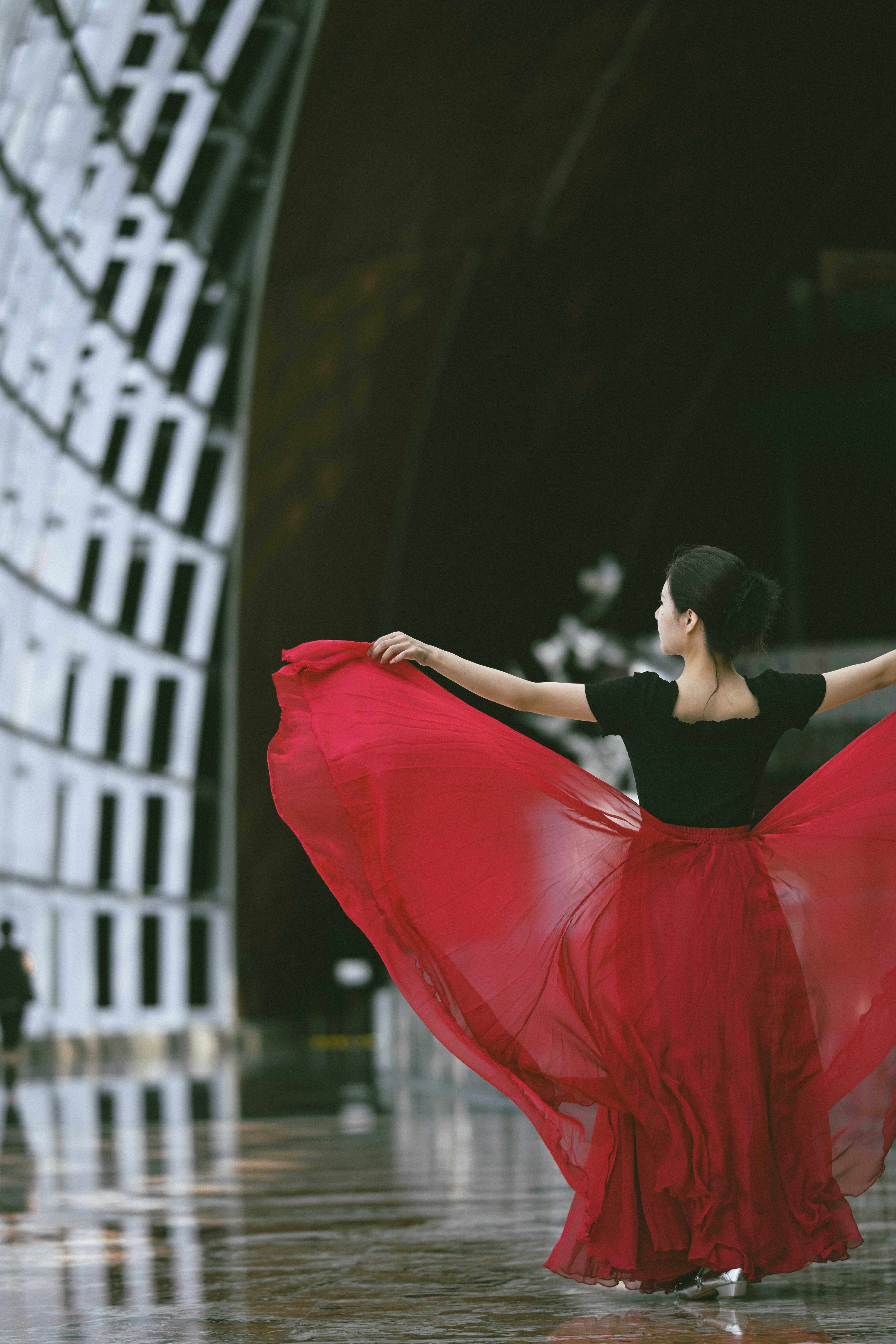 Red Silk in Motion: A Dancer Turns Under a Modern Arch