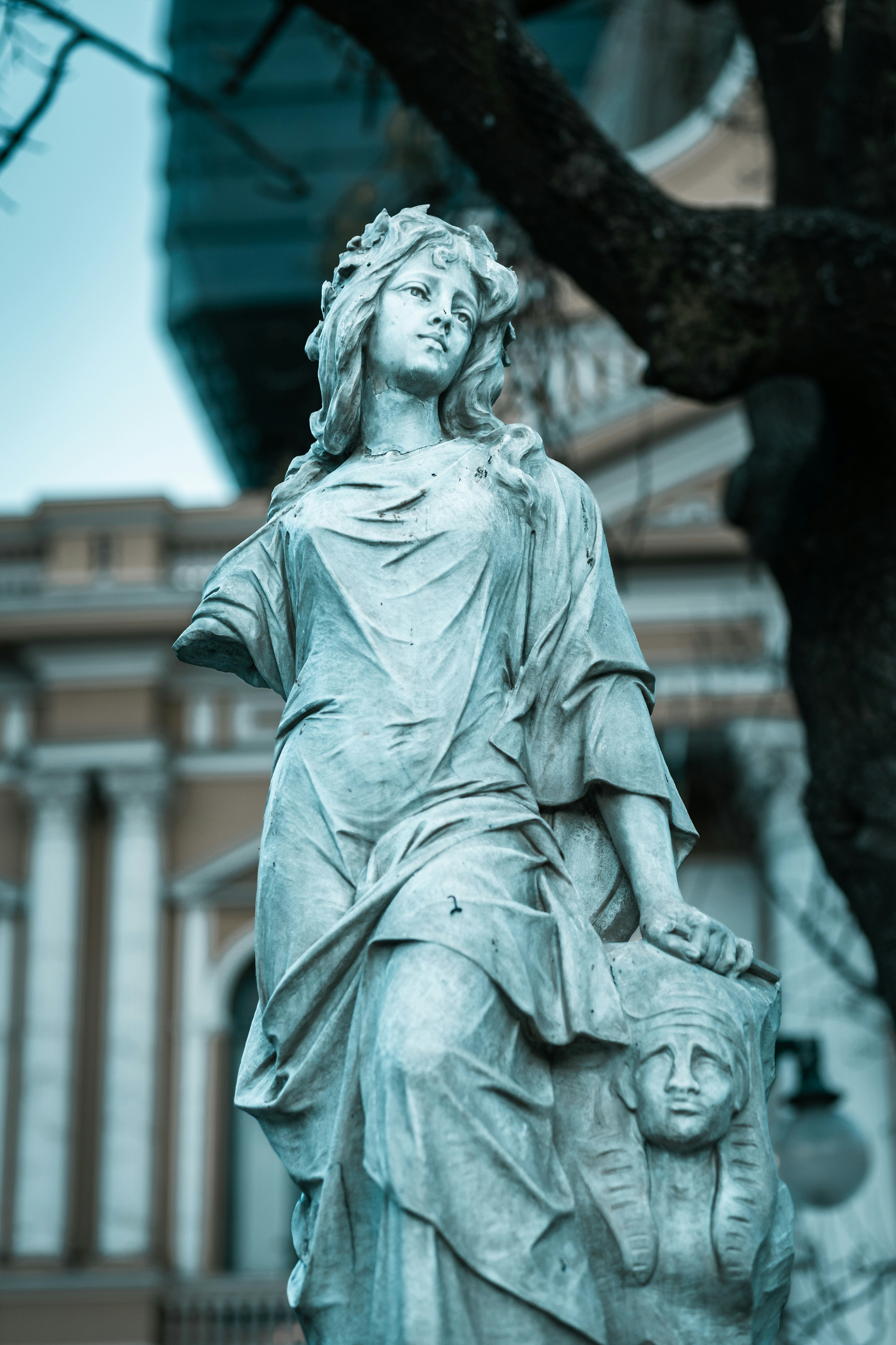 Statue of Serenity: A Woman and Crowned Face Beneath Urban Canopy