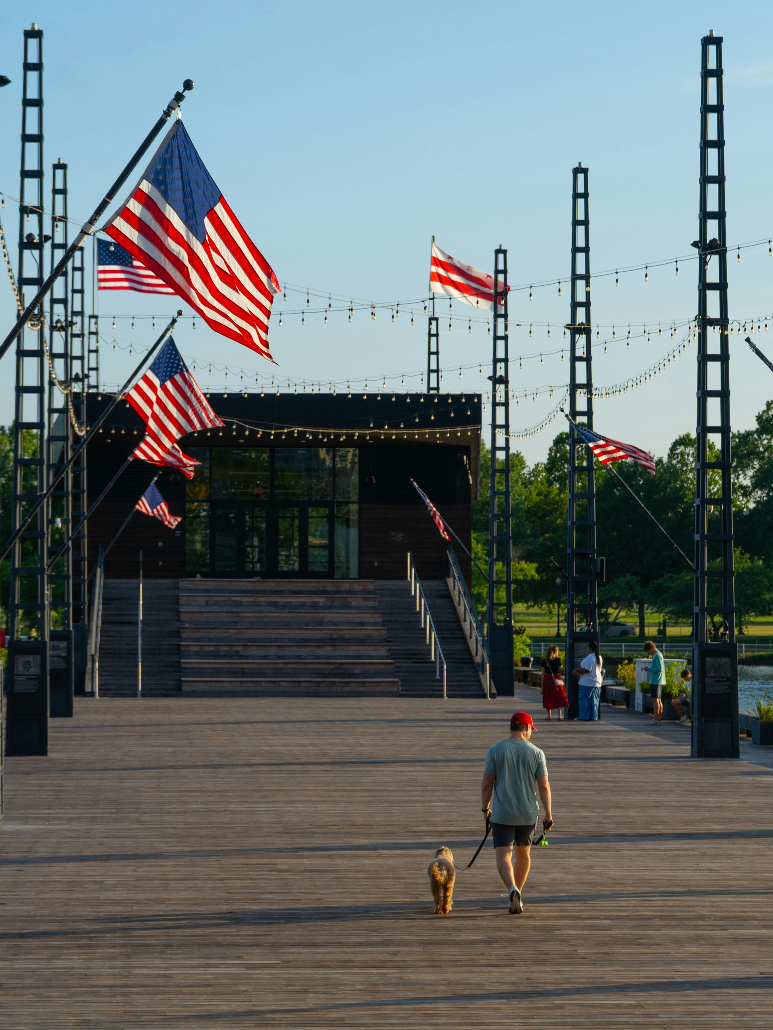 Flaglit Promenade: A Lone Couple and Their Pooch Walk Toward the Stage