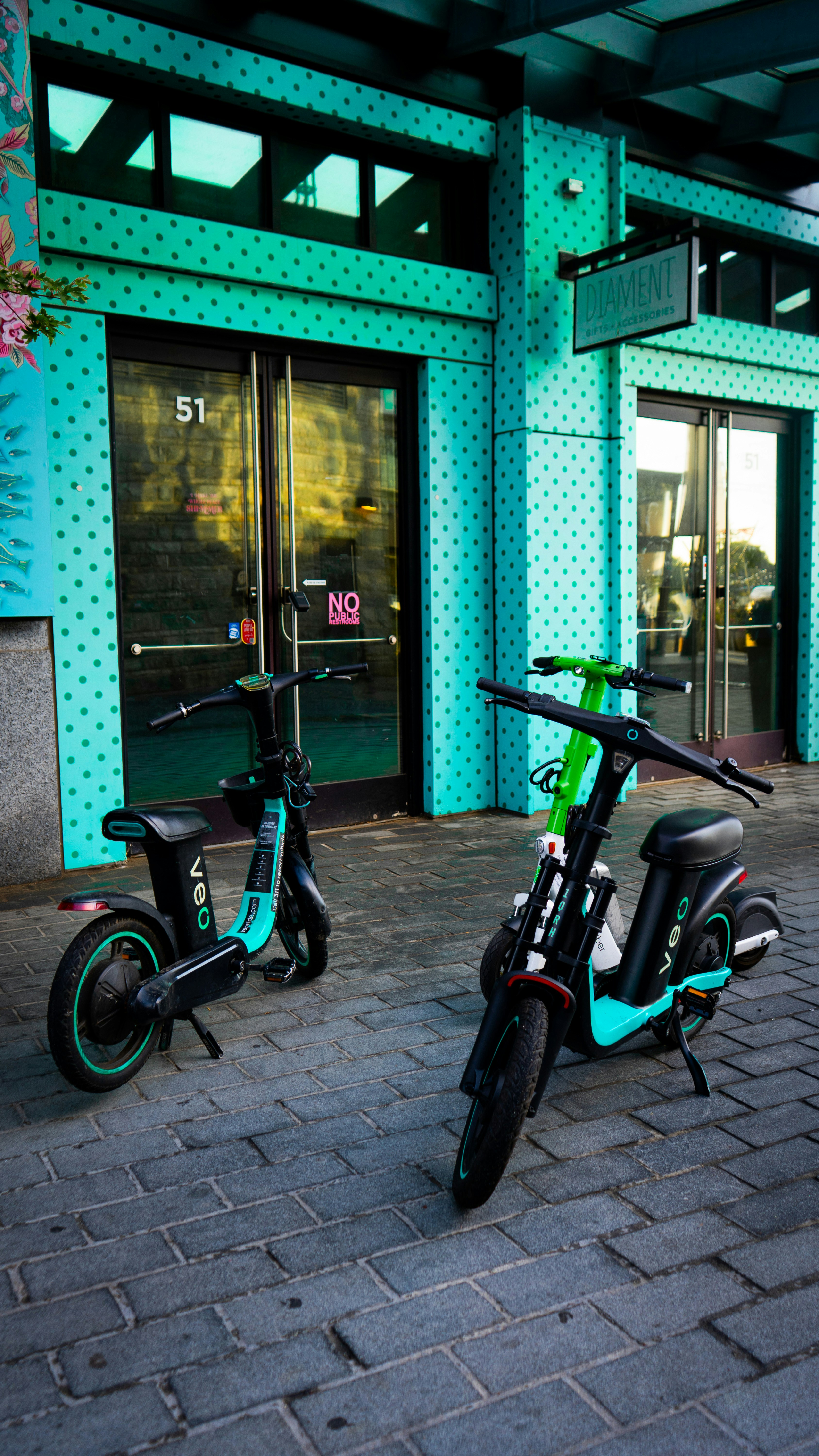 Minted Miles: turquoise storefront and electric scooters at the neon-lit corner