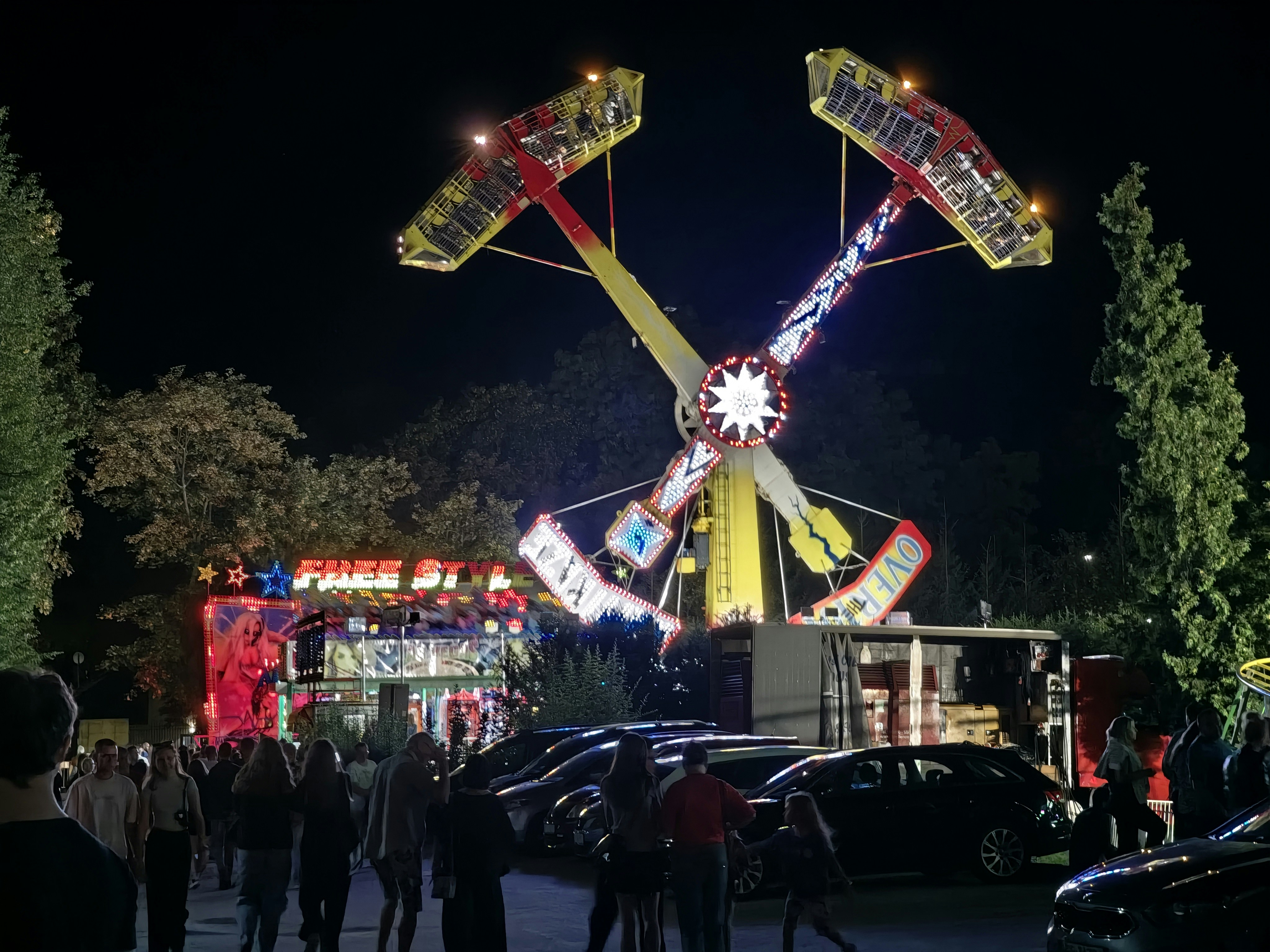 Nighttime Thrill: A Neon-Crowned Ride Amid a Crowded Fairground