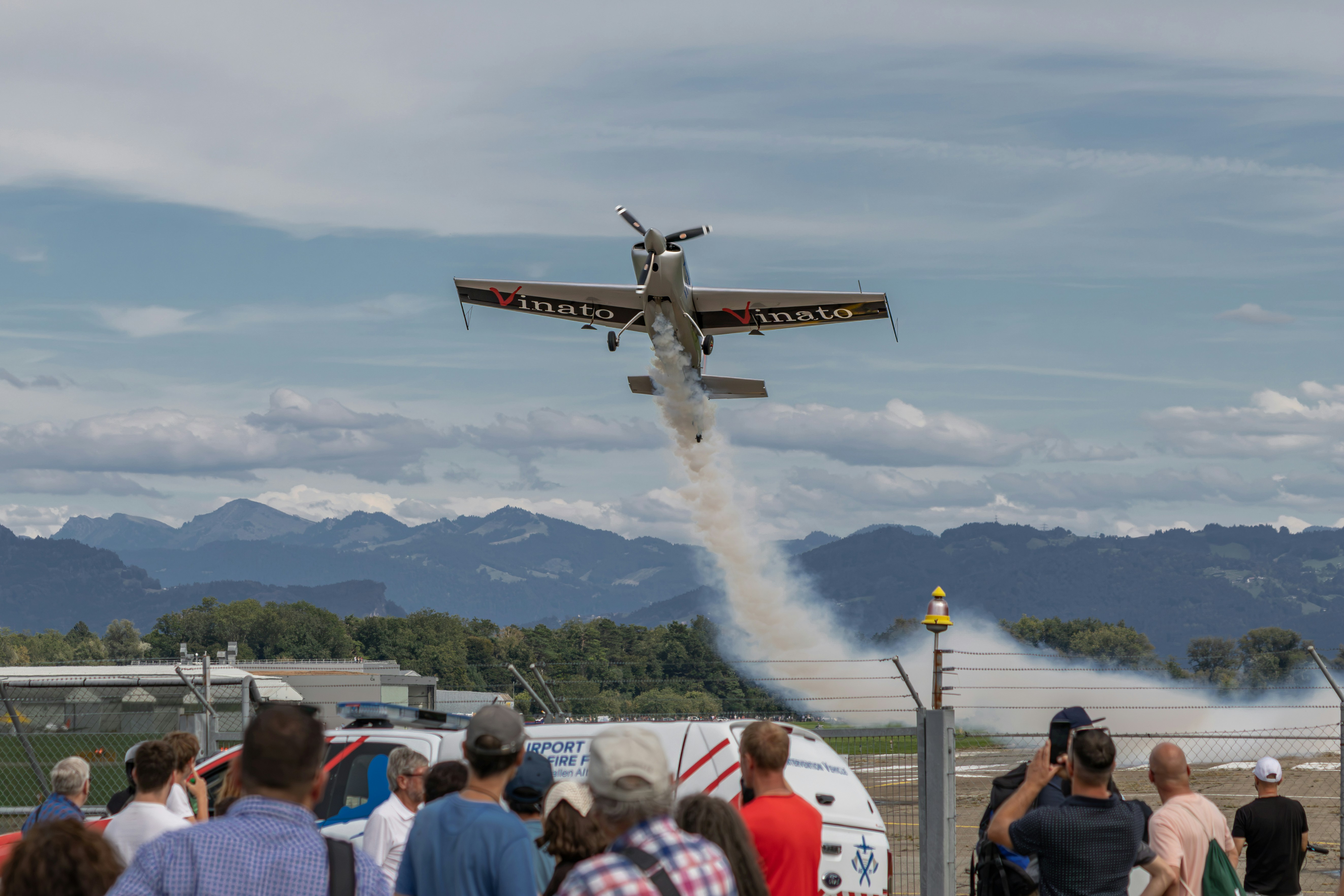 Skybound Lift-off: A Parked Crowd Watches a Biplane Propel Itself Skyward
