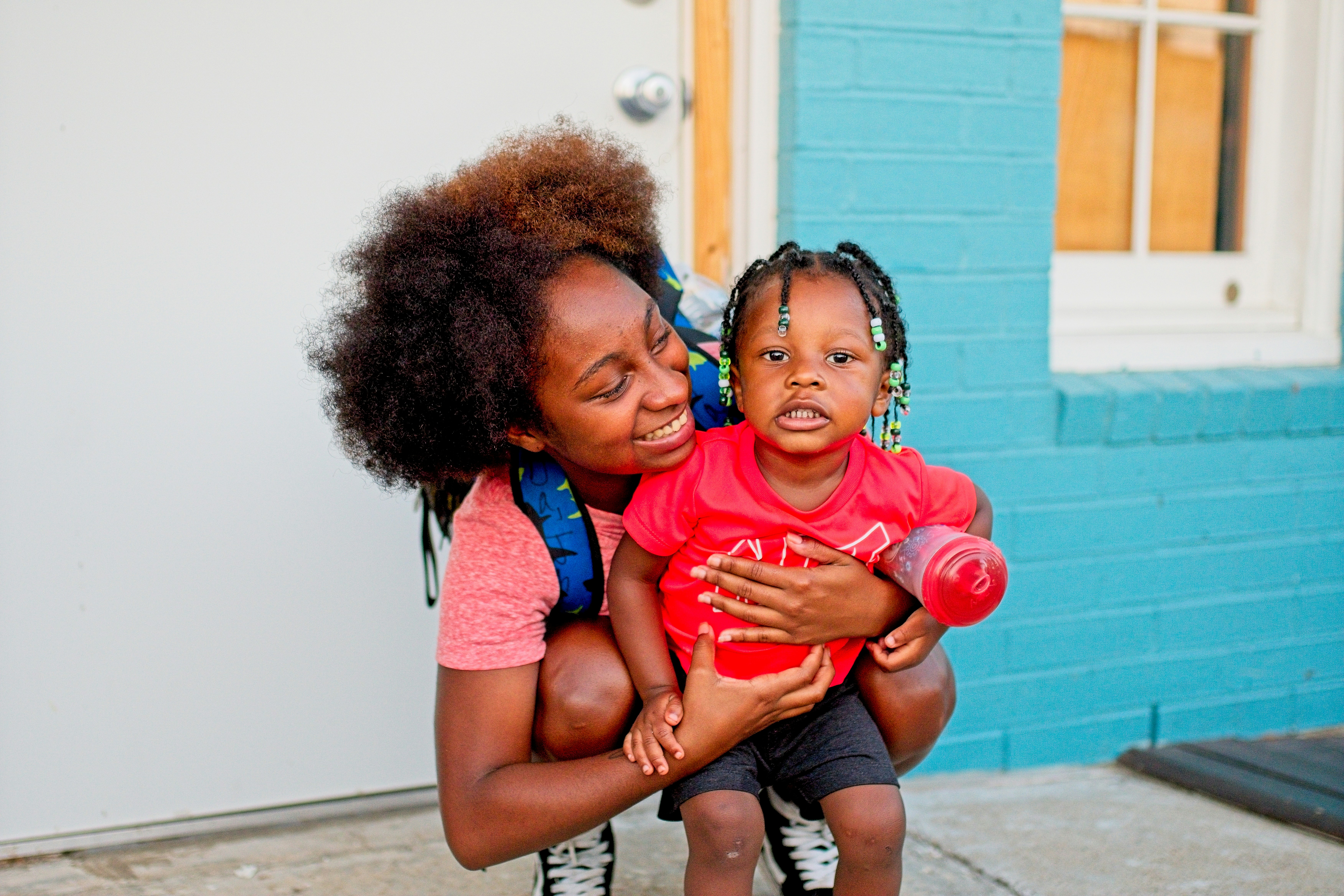 Holding Hope: A Mother’s Smile and Child’s Cheer in Sunlit Street