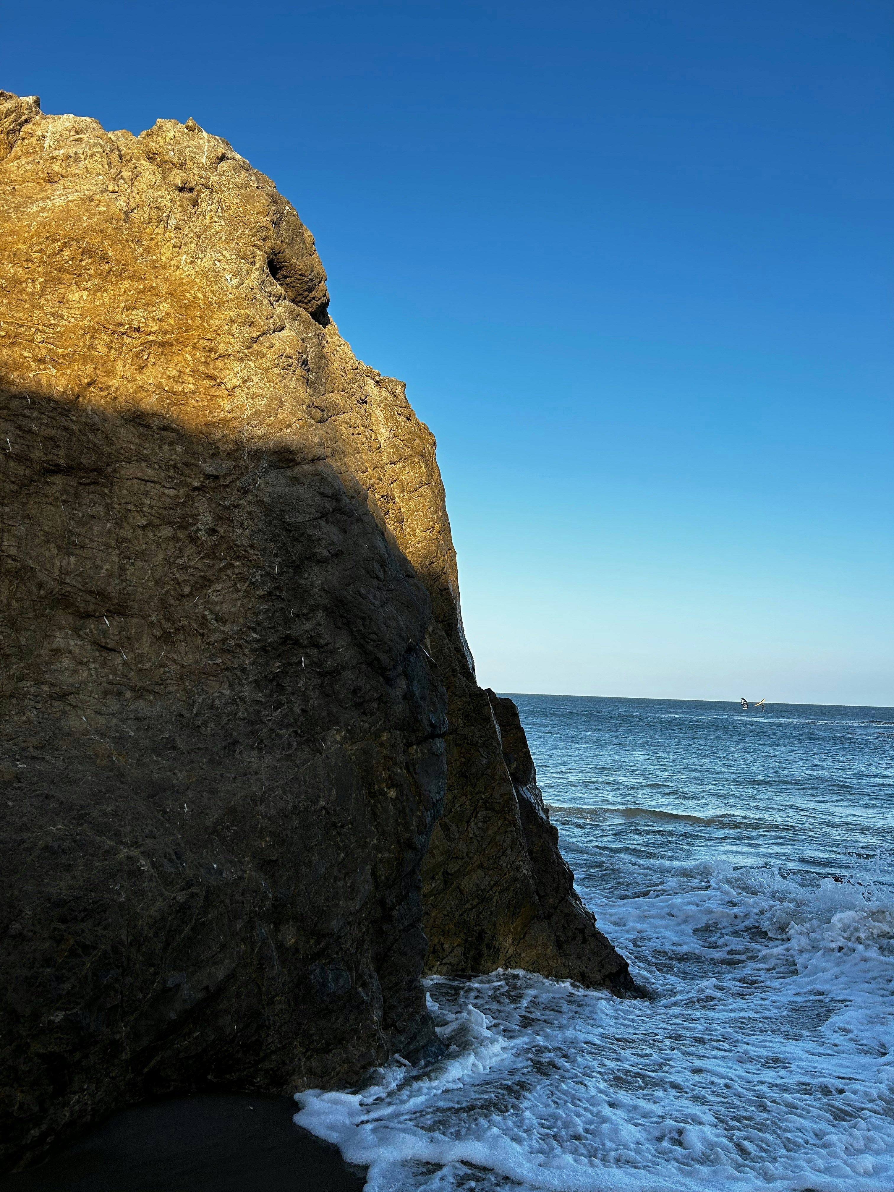 Coastline Sentinel: Sunlit Cliff Meeting Wrapping Waves