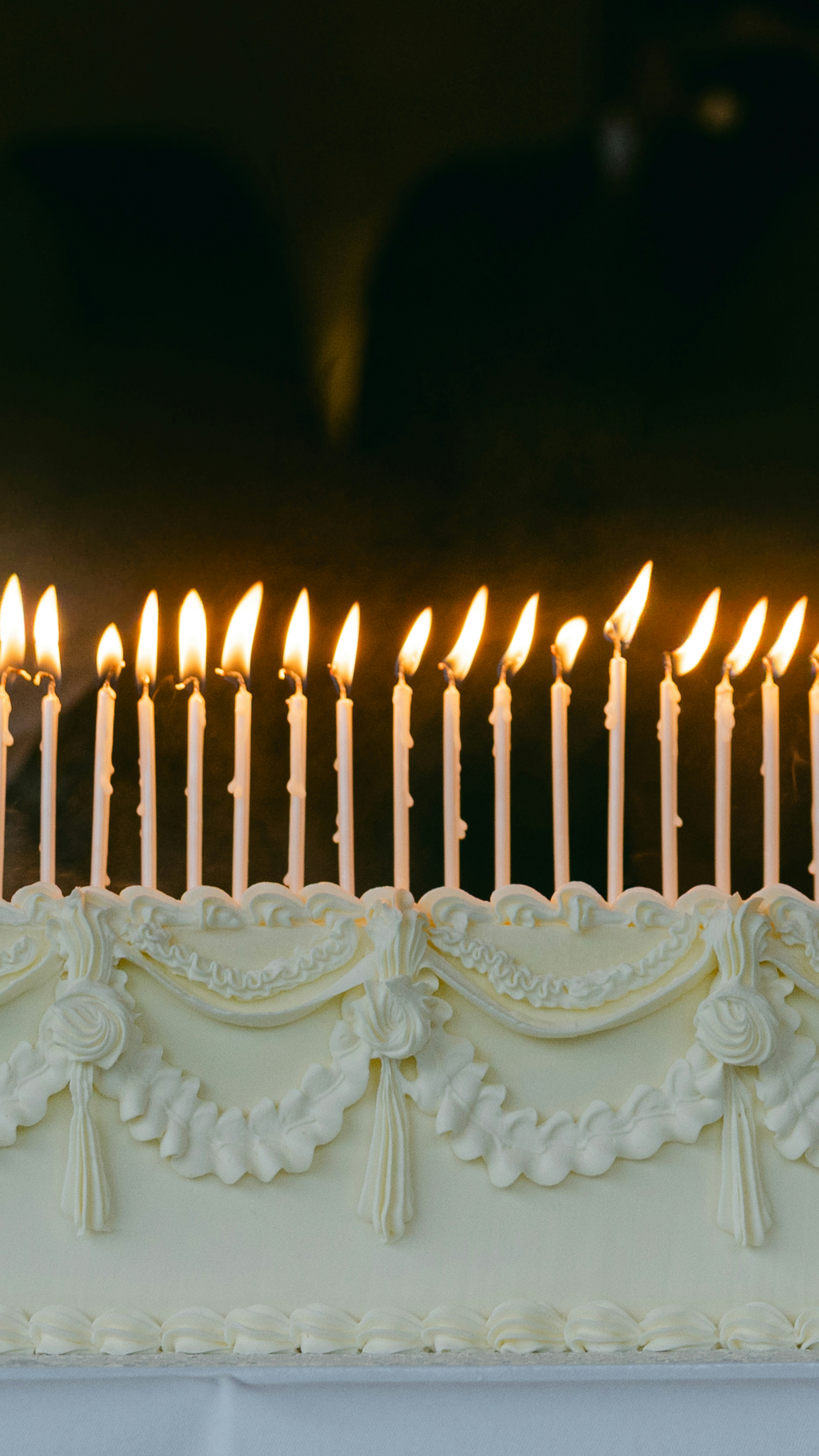 Candlelit Cascade: A Row of Birthday Flames Above Ornate Frosting