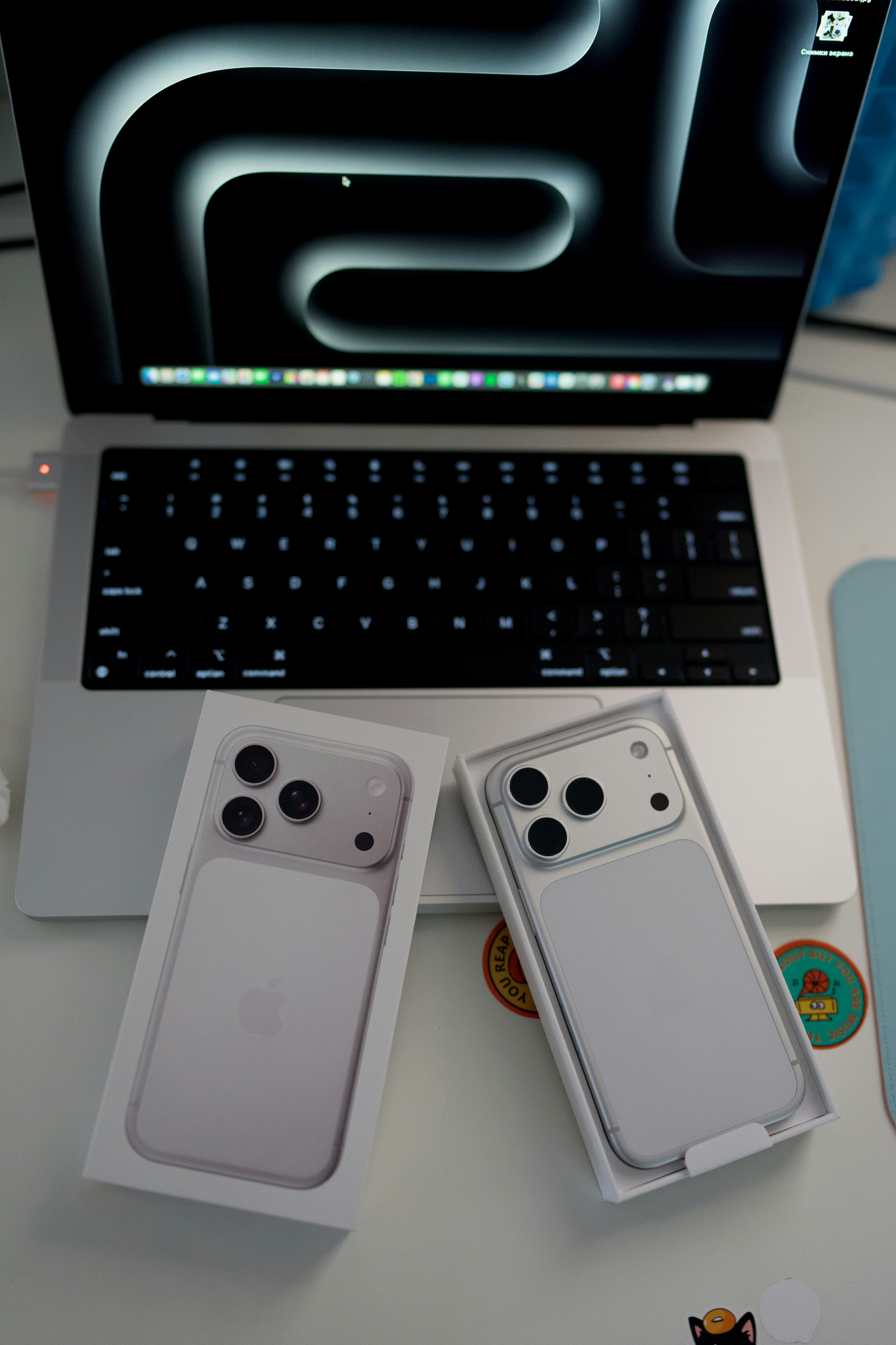 Tech Unboxed: Laptops and iPhone Pro Boxes Resting Beneath a Backlit Screen